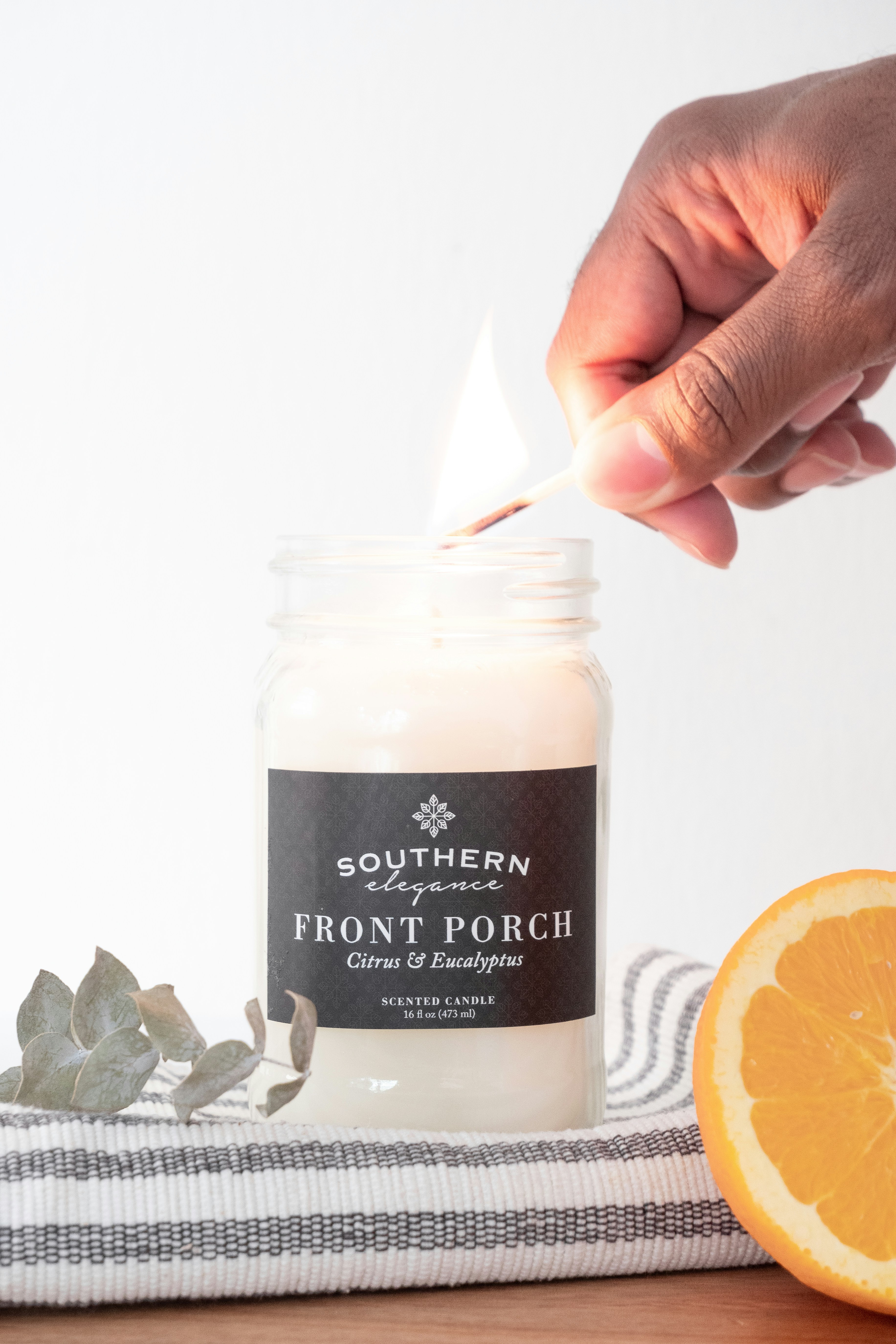 A hand lighting a candle with a match.