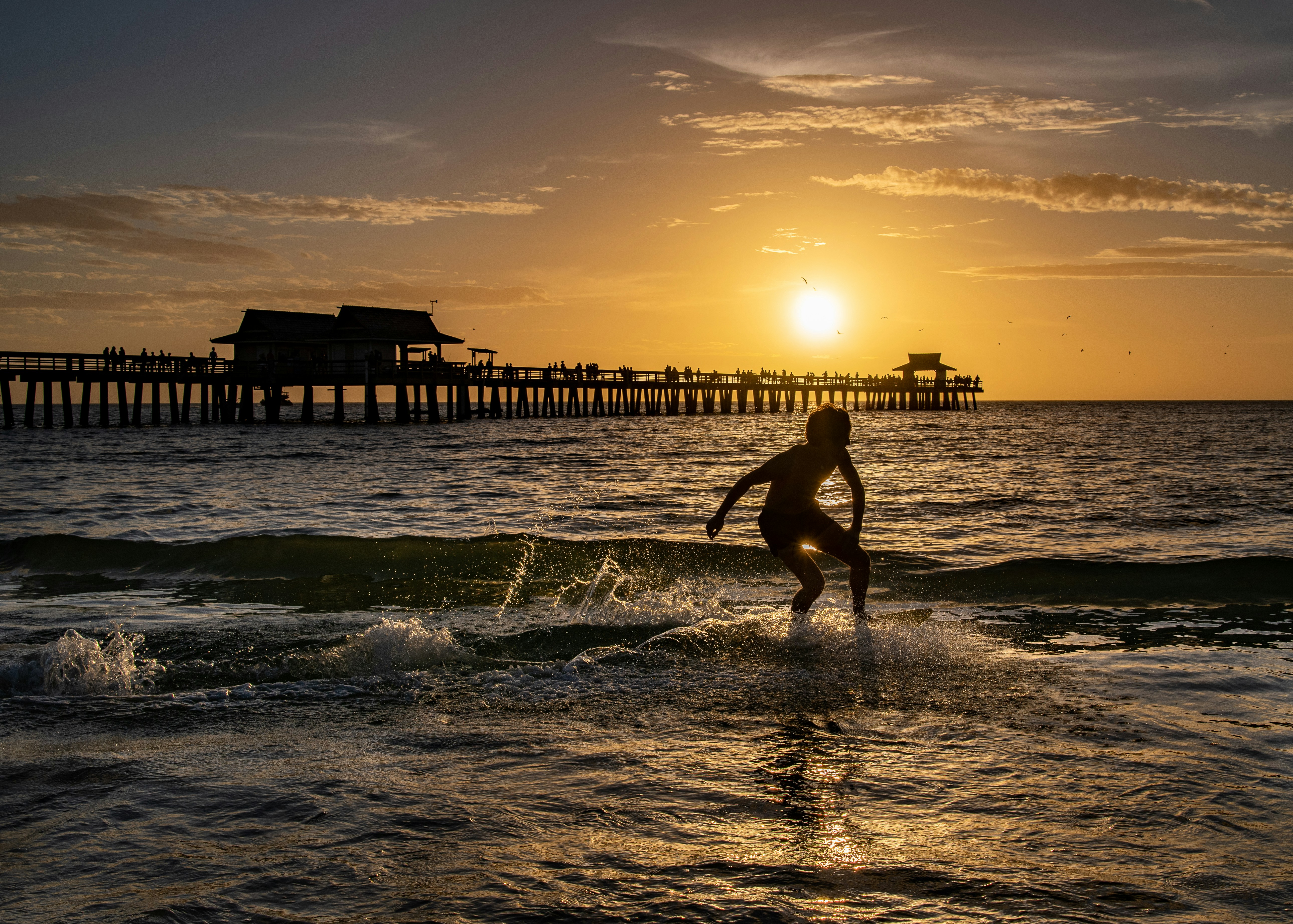 A person riding a surf board on a body of water photo – Free Naples ...