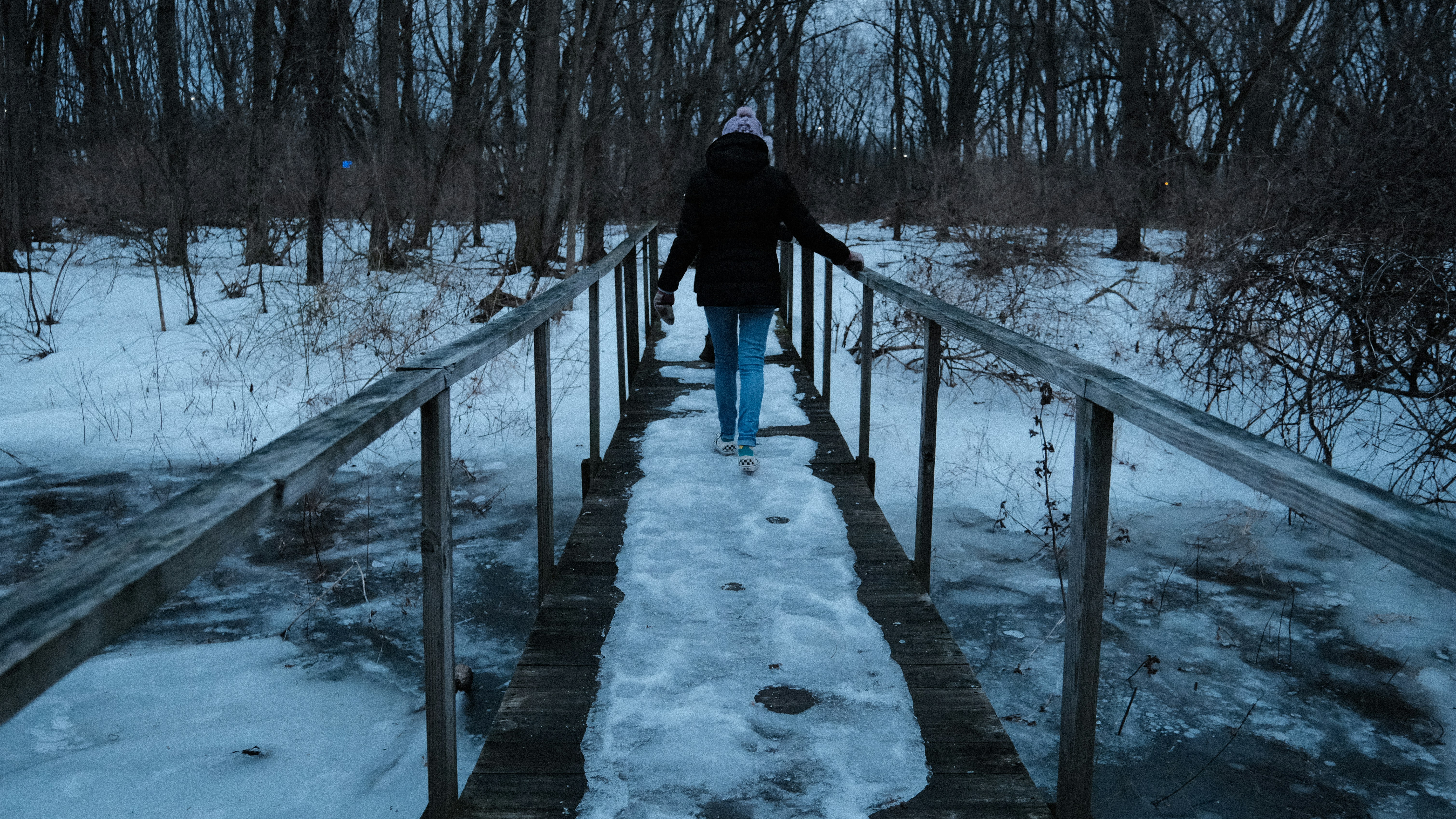 Frostbound Crossing: A lone walker on a narrow icy bridge