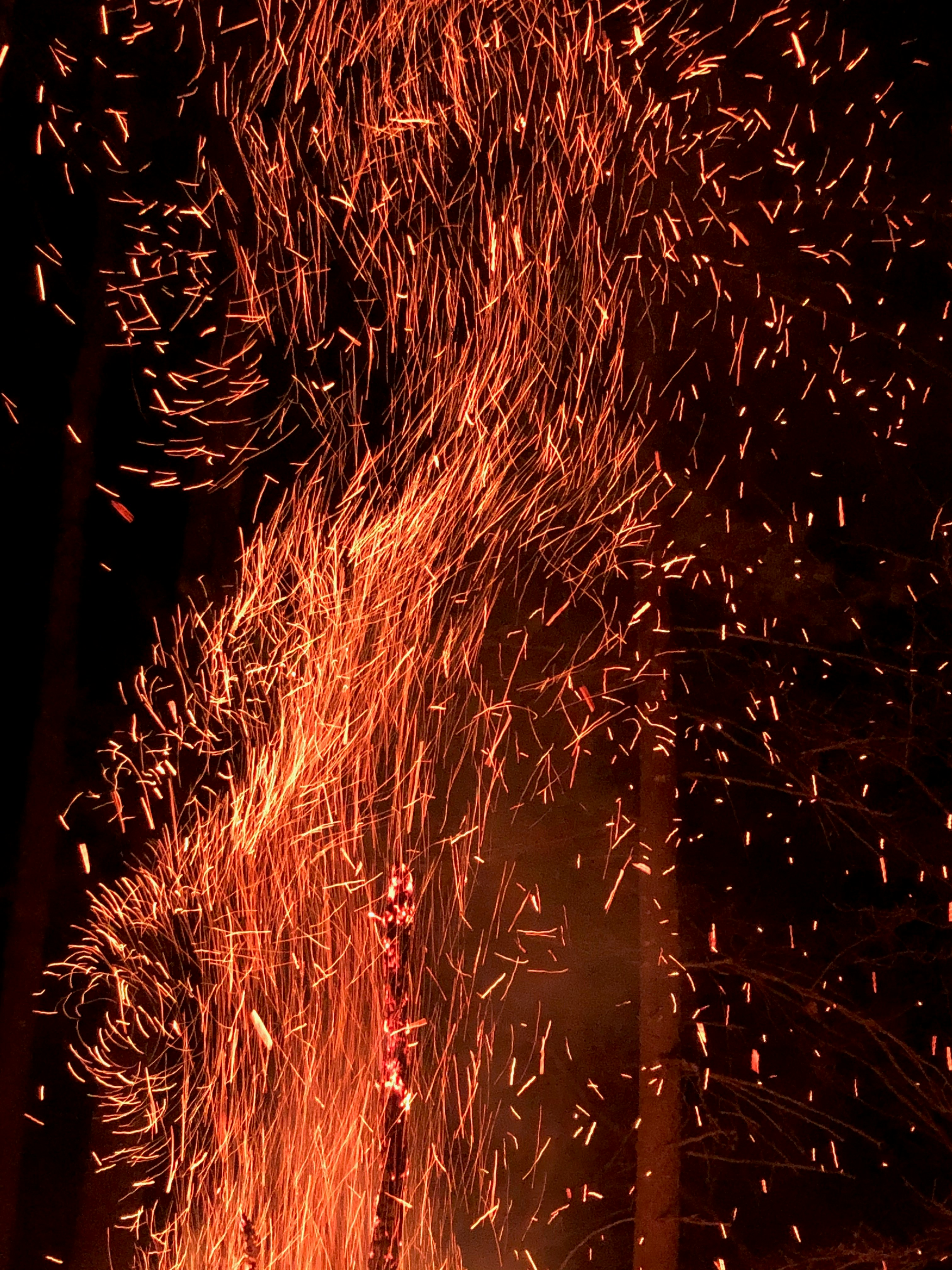 Sparks and embers rise against a dark backdrop, creating a mesmerizing display of light and movement. The scene captures the essence of a fire's energy.