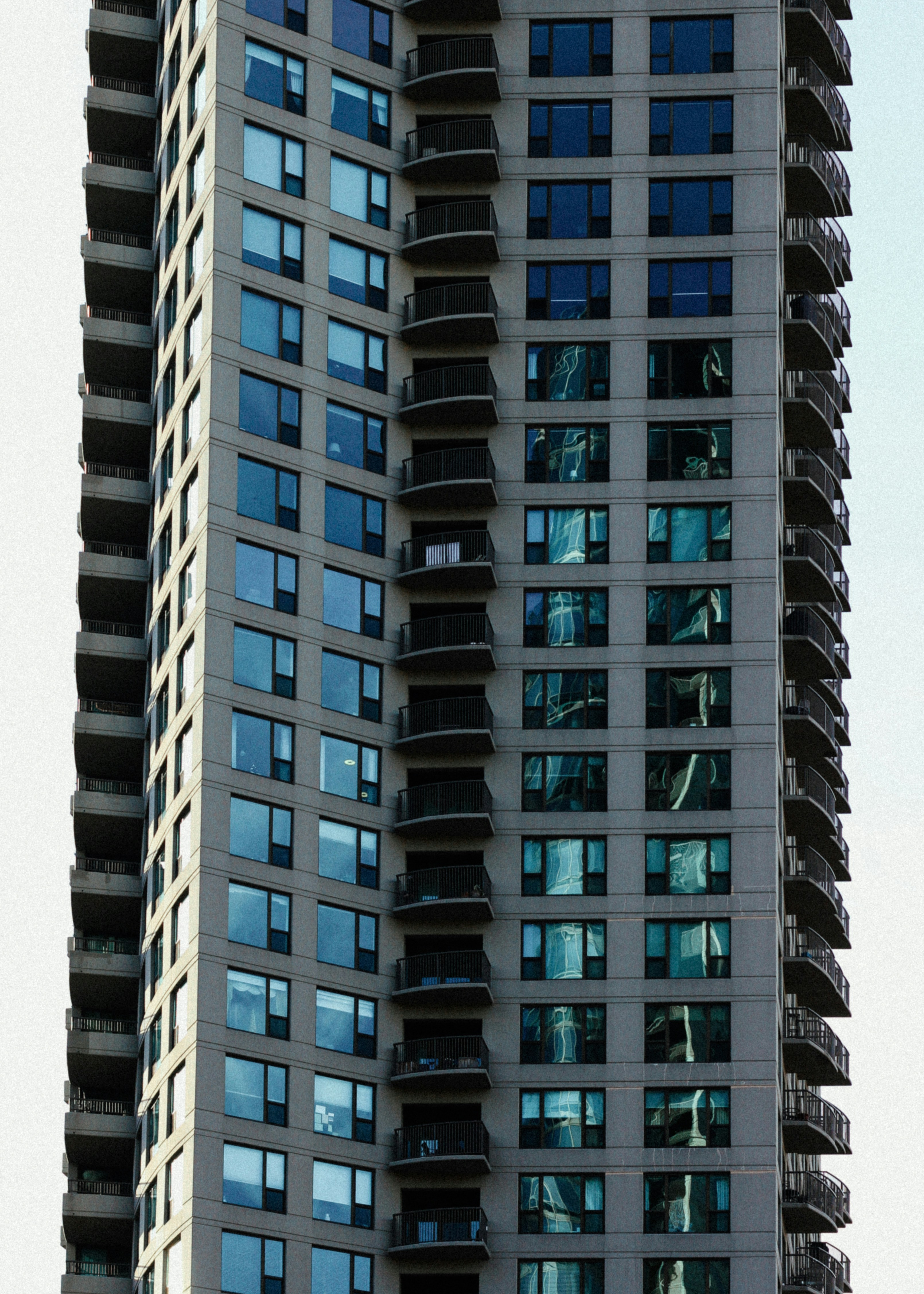 Modern residential tower showcasing a façade of reflective windows and balconies, capturing the essence of urban architecture.