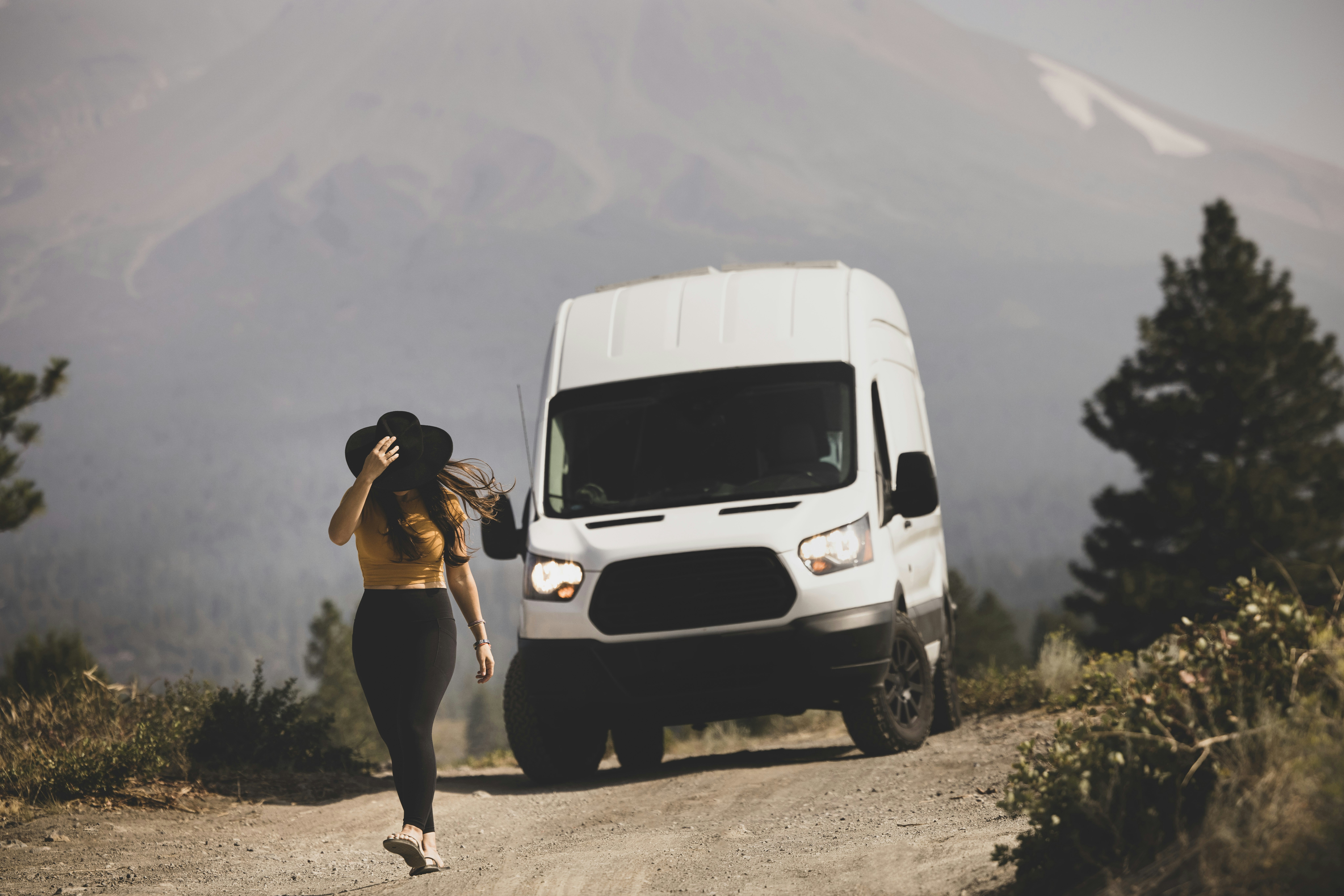 Dust on the Horizon: A lone photographer and a tilted van on a mountain dirt road
