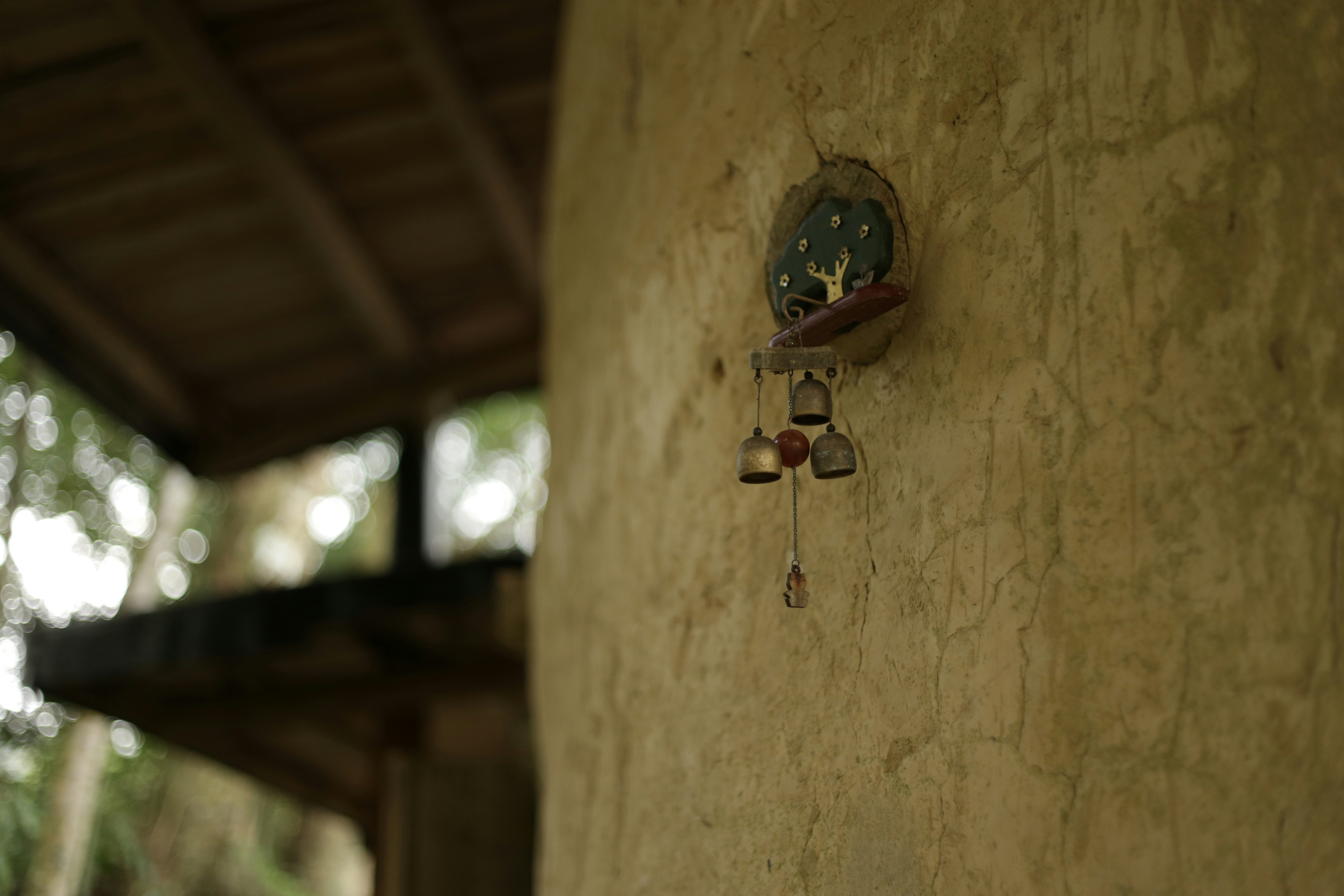 Wind chime on a sun-warmed adobe wall under a shaded veranda