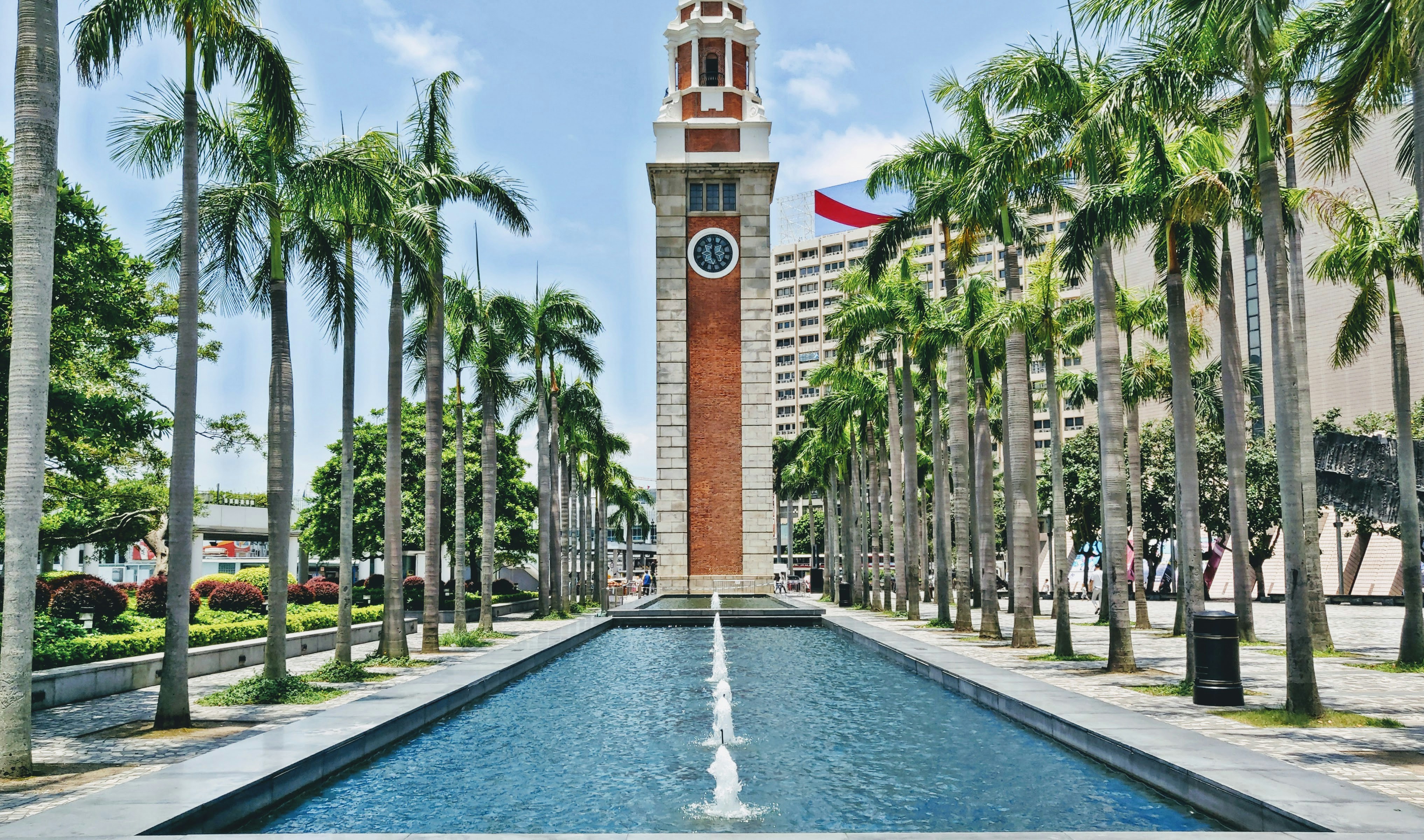 Convergence of Time: Clock Tower Framed by a Palm-Row Canal