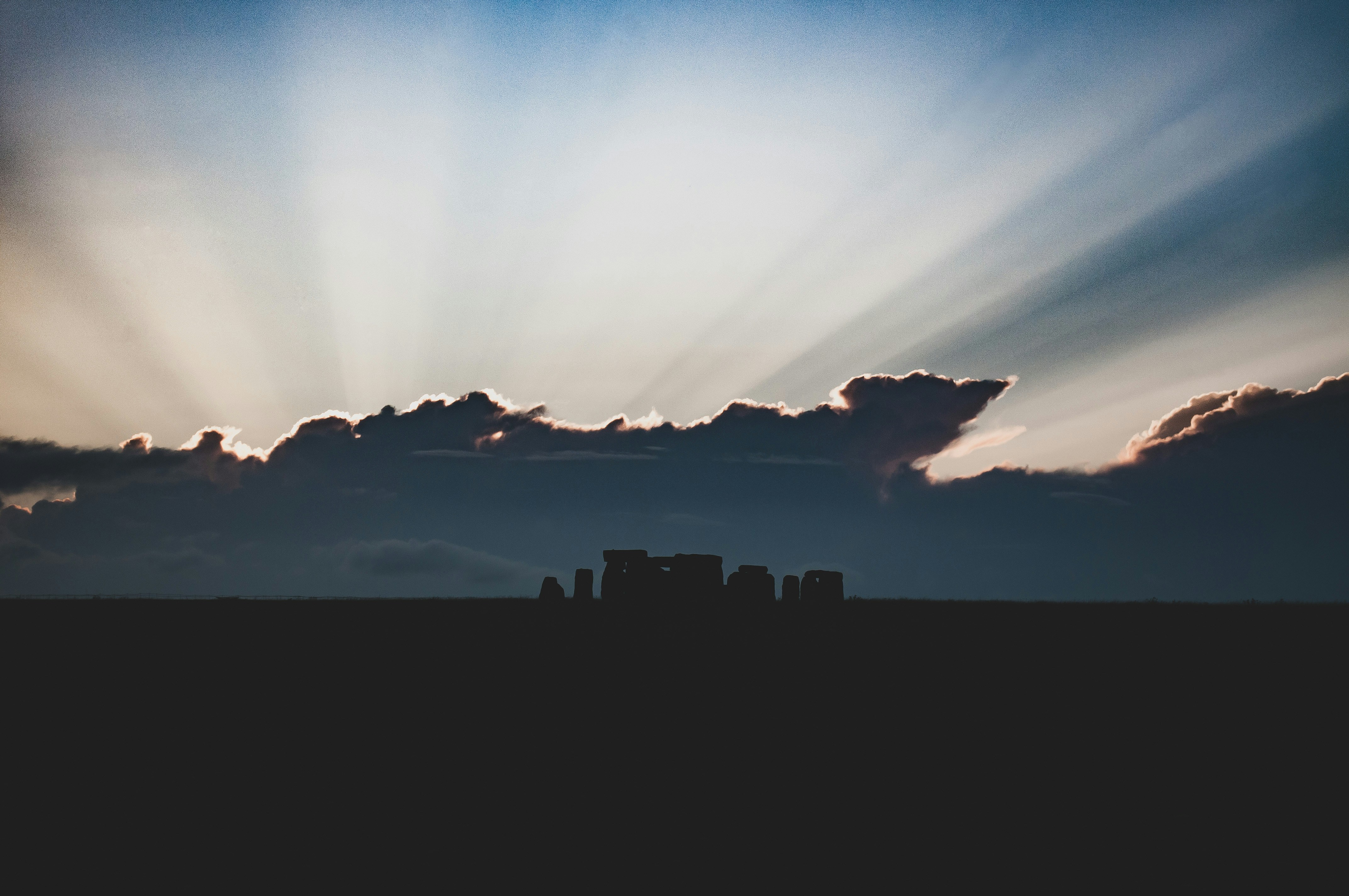 Distant Monoliths: Silhouettes Beneath a Radiant Break in the Sky