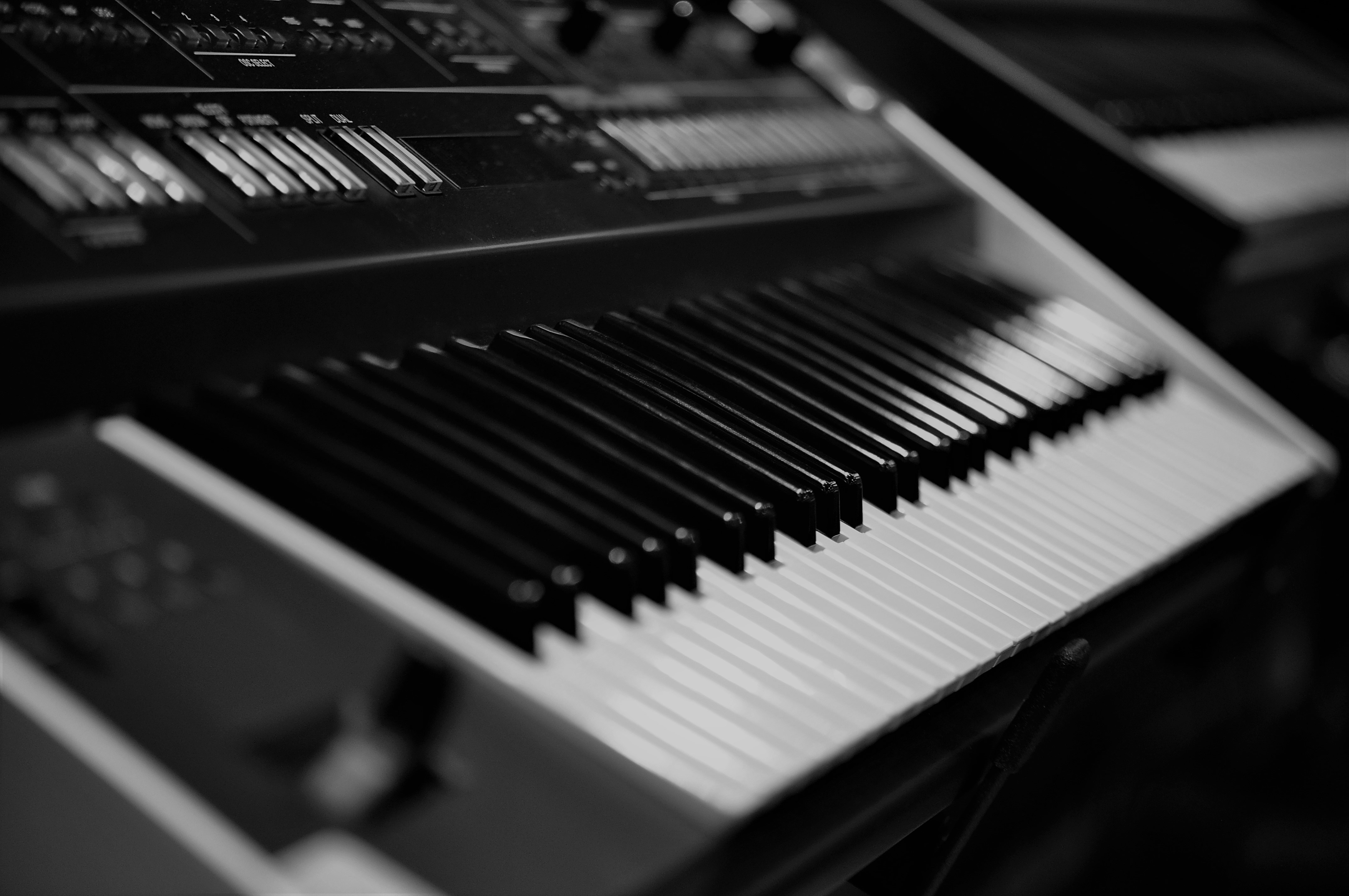 Close-up of a keyboard showcasing black and white keys with a blurred control panel in the background.