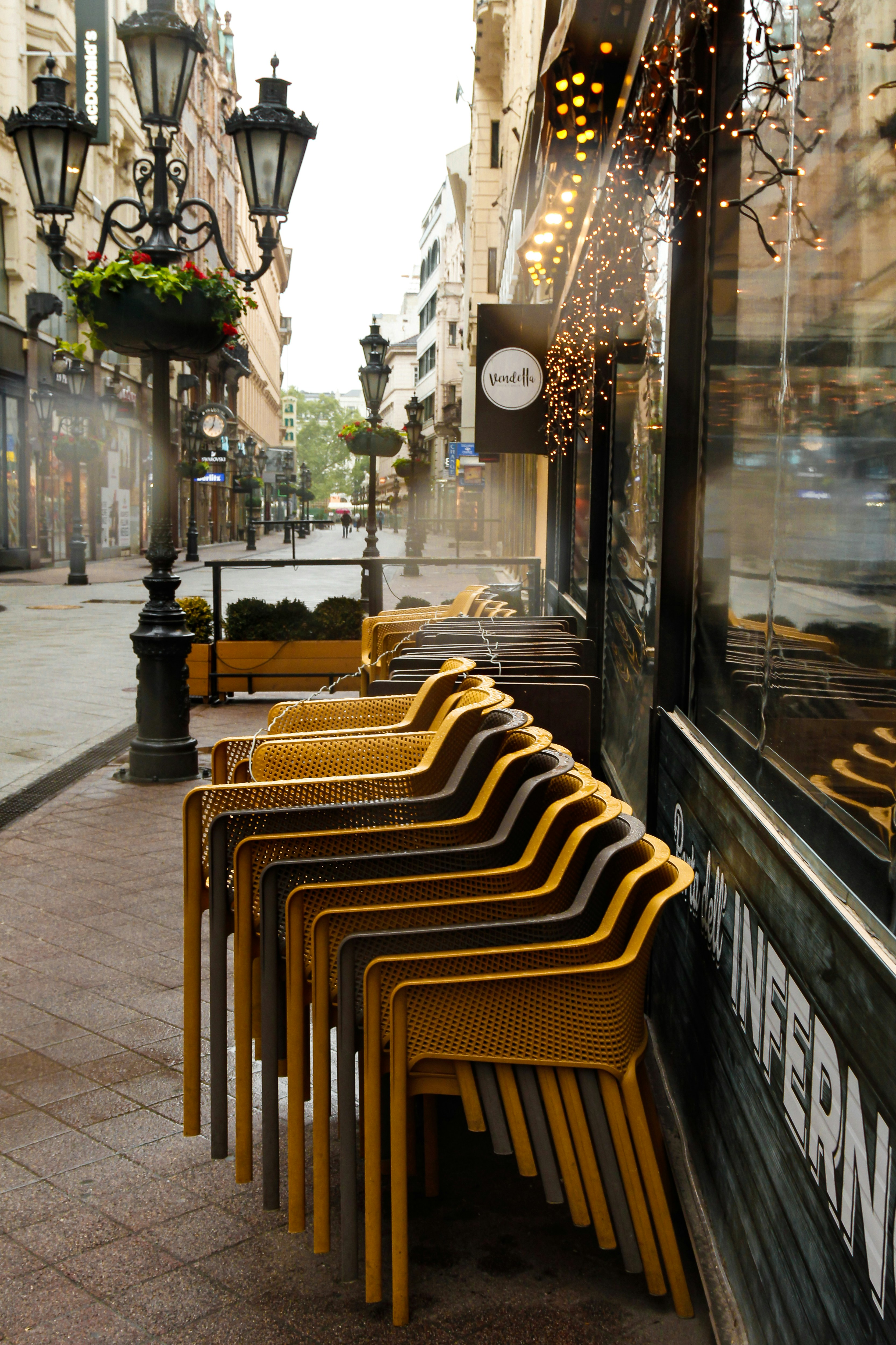 Amber-Chair Cascade on a Quiet European Street at Dusk