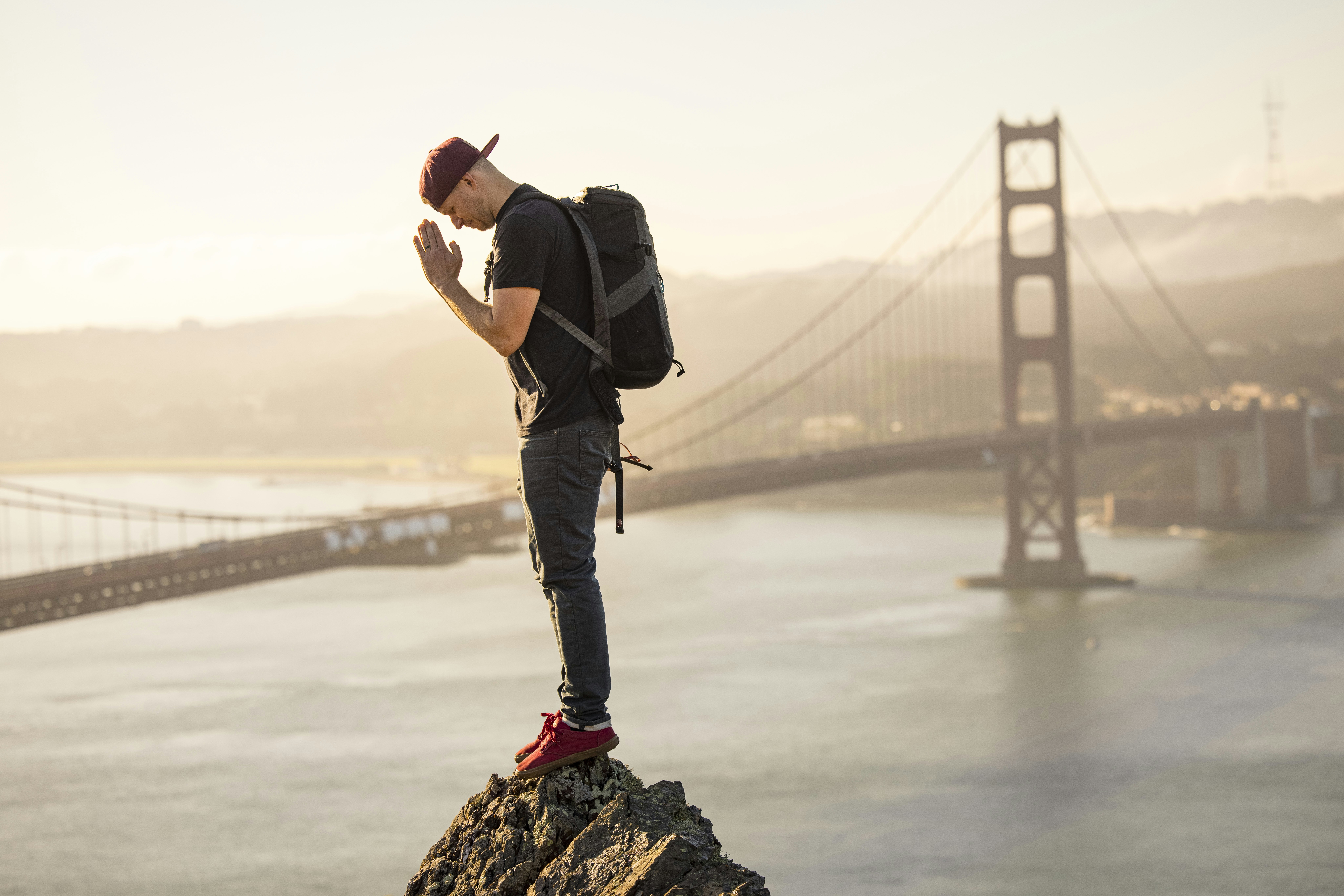 Man in black t-shirt and blue denim jeans standing on rock near golden ...