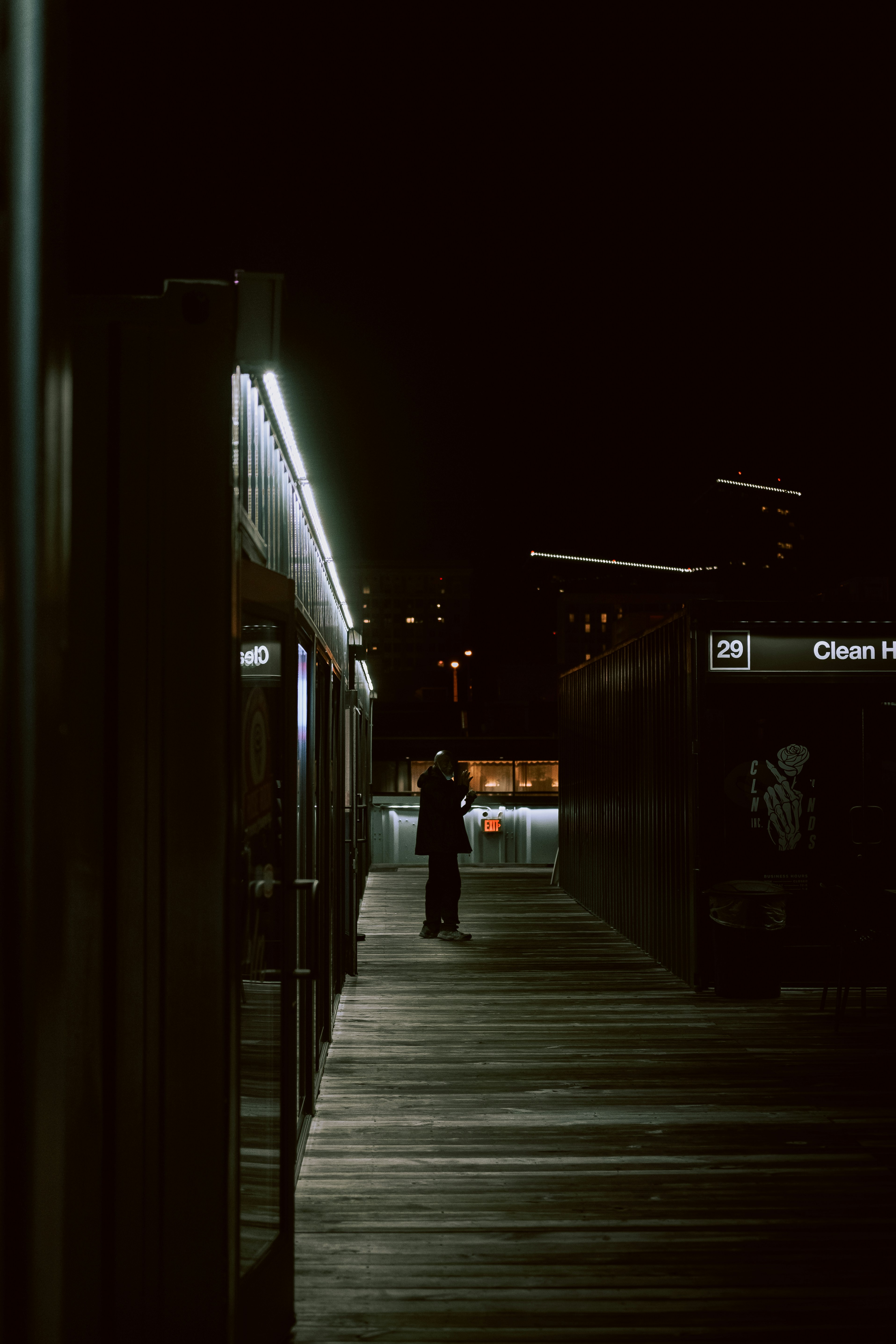 Person standing in a dimly lit urban alleyway at night.