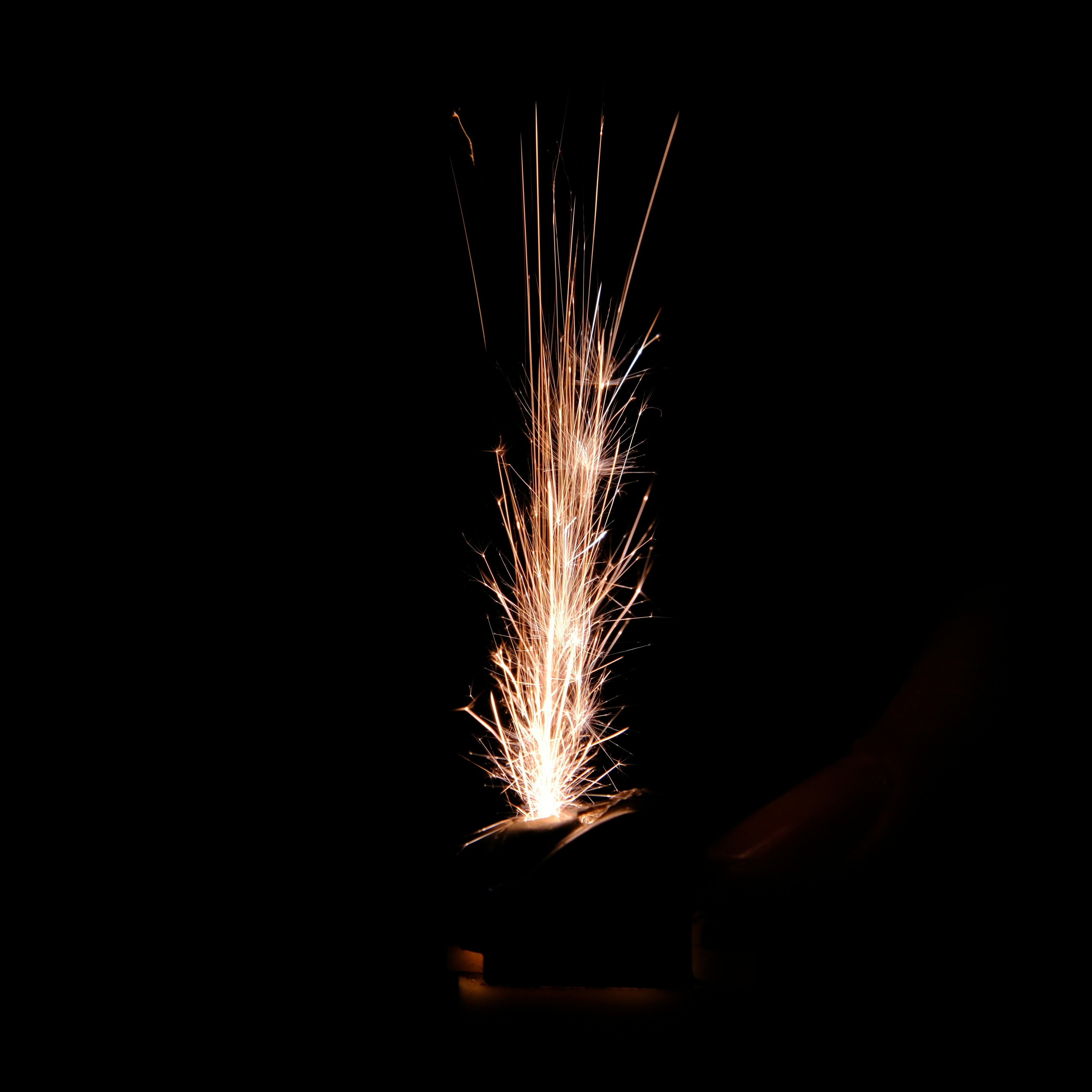 fire spark from the lighter isolated on black background. | a person holding a lit sparkler in their hand