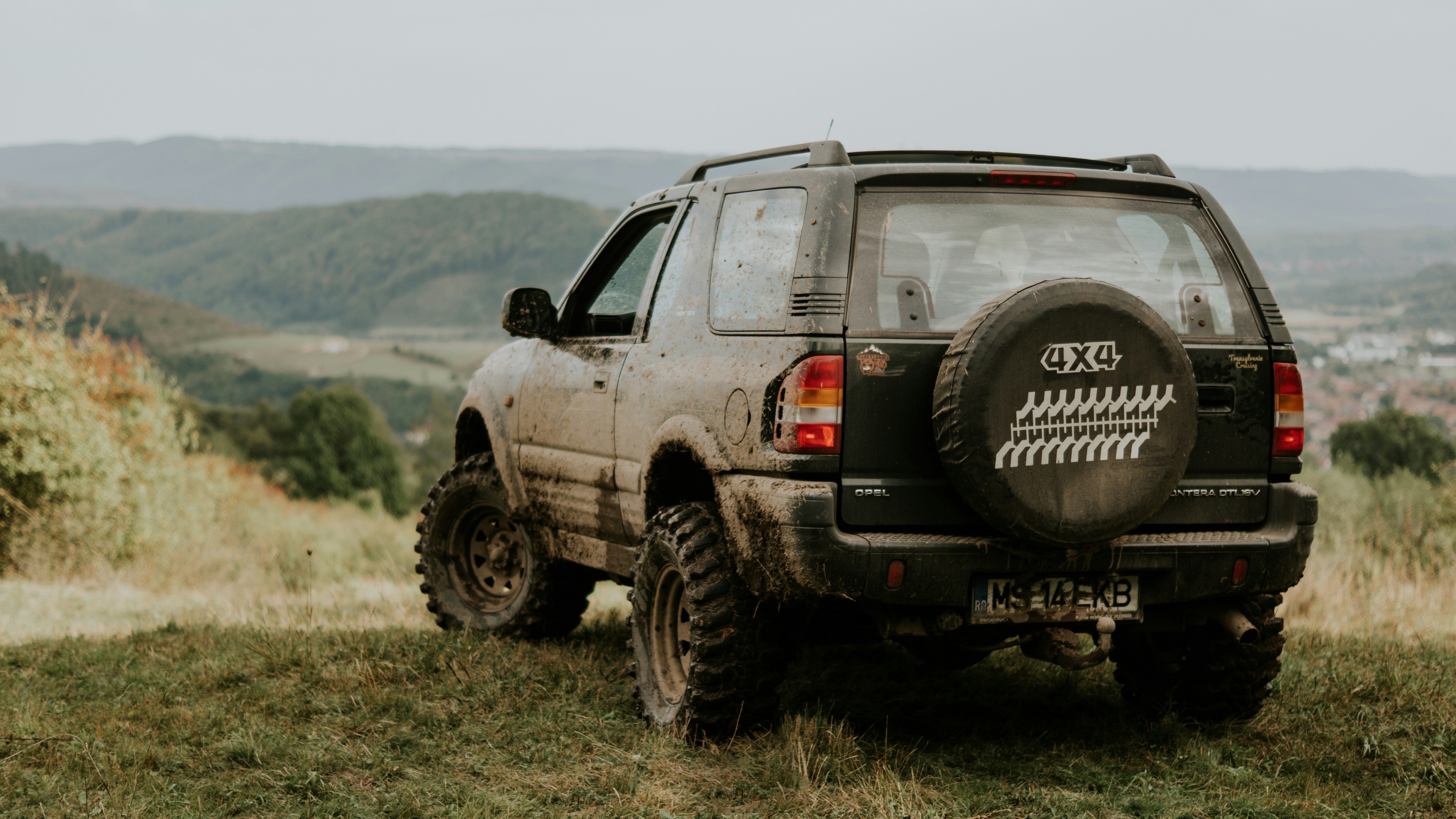 Mud-Streaked SUV Reigning Over a Rolling Hillscape