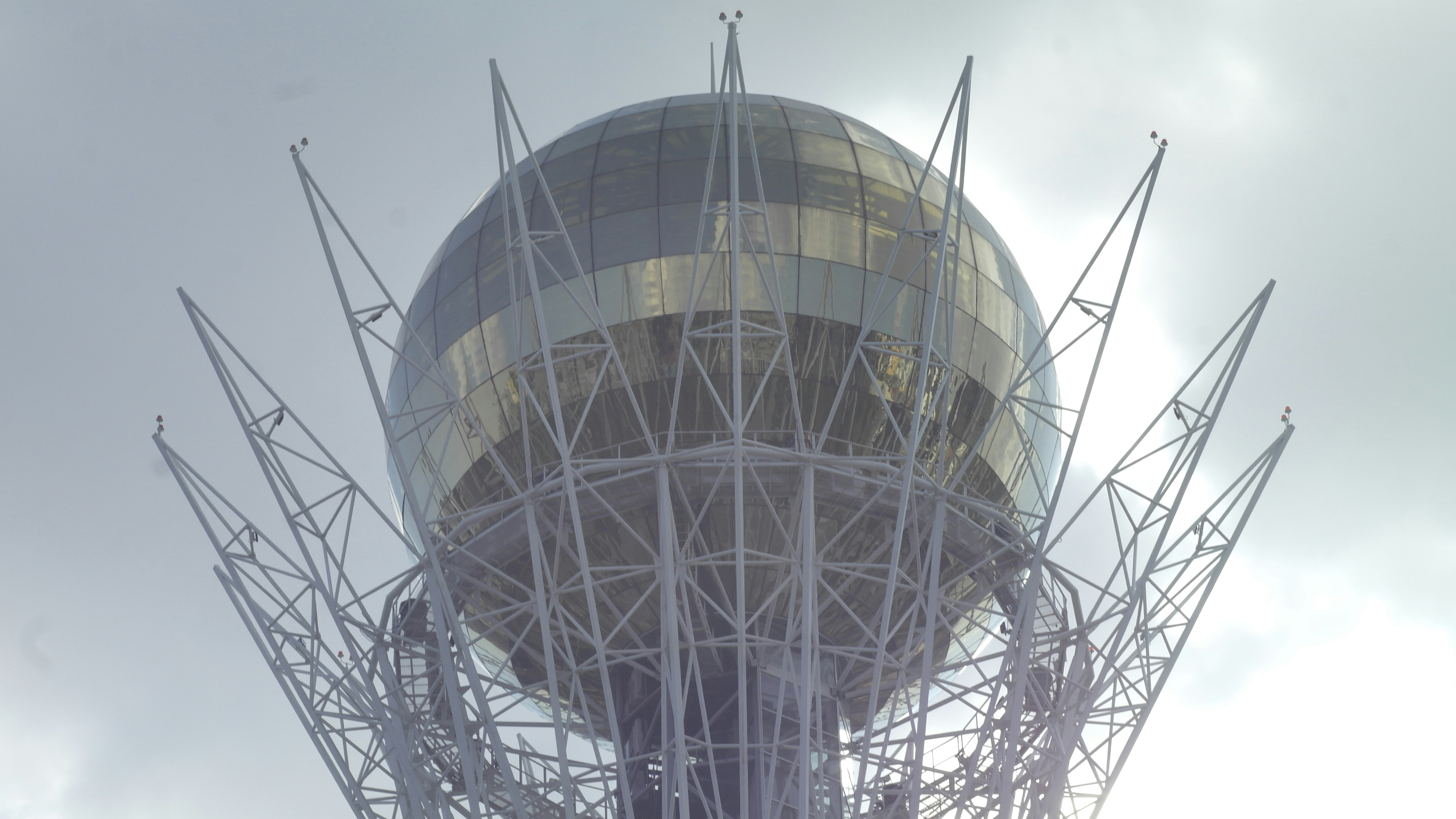 Spherical structure atop a network of steel beams against a cloudy sky.