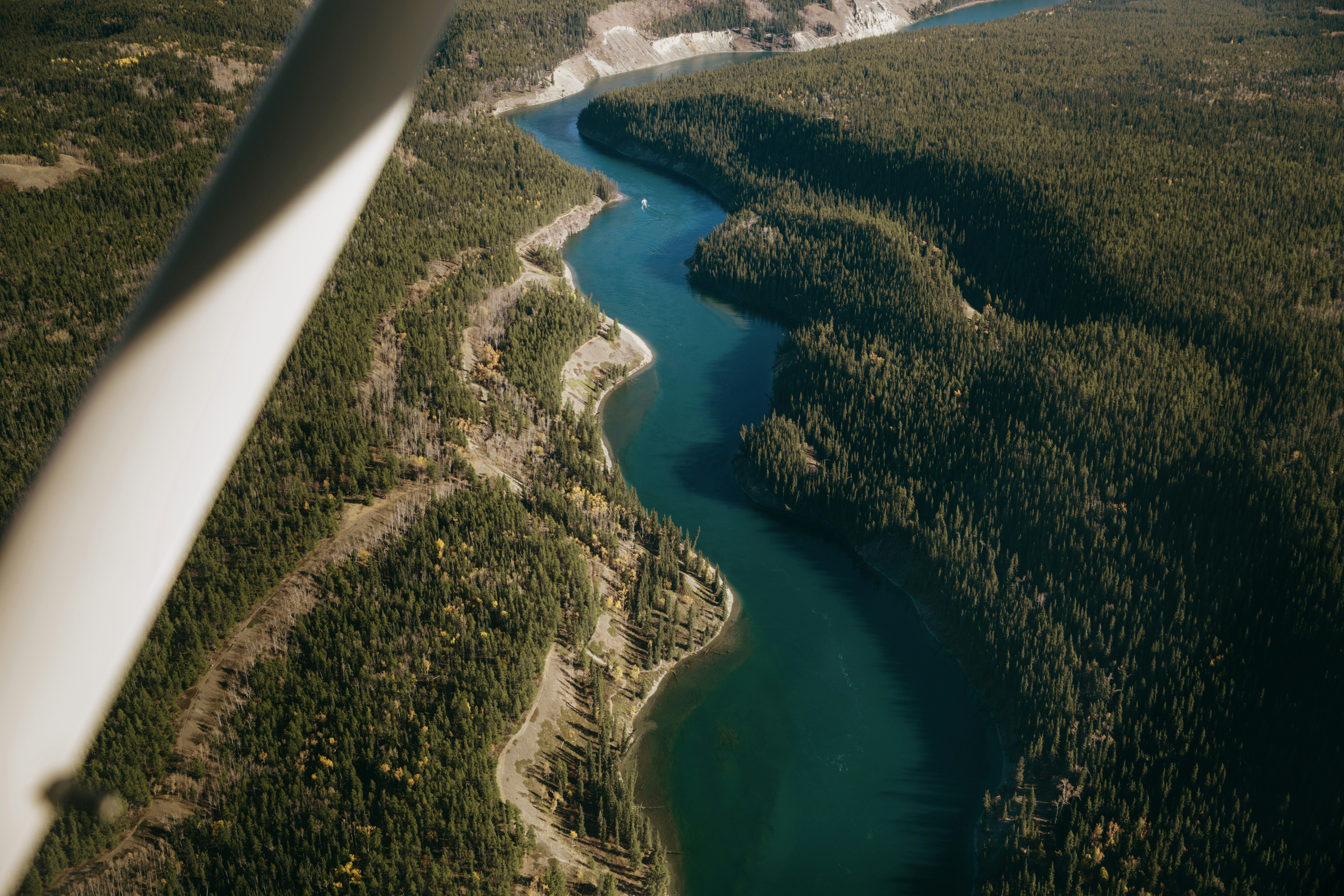 Curved Azure Corridor: Aerial Glide Over Verdant River Bend