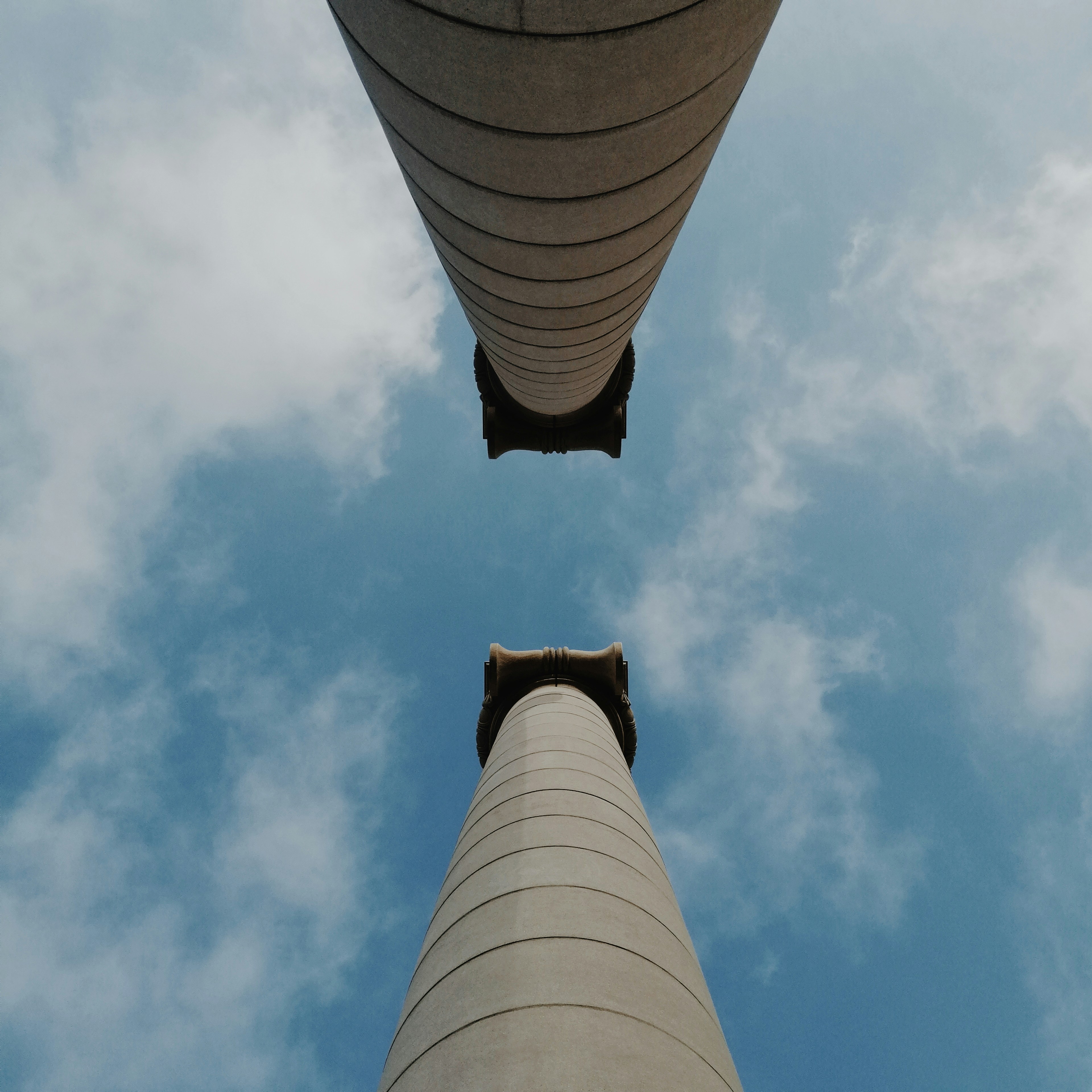 Two towering columns reach towards a cloudy sky, showcasing intricate detailing at their tops.