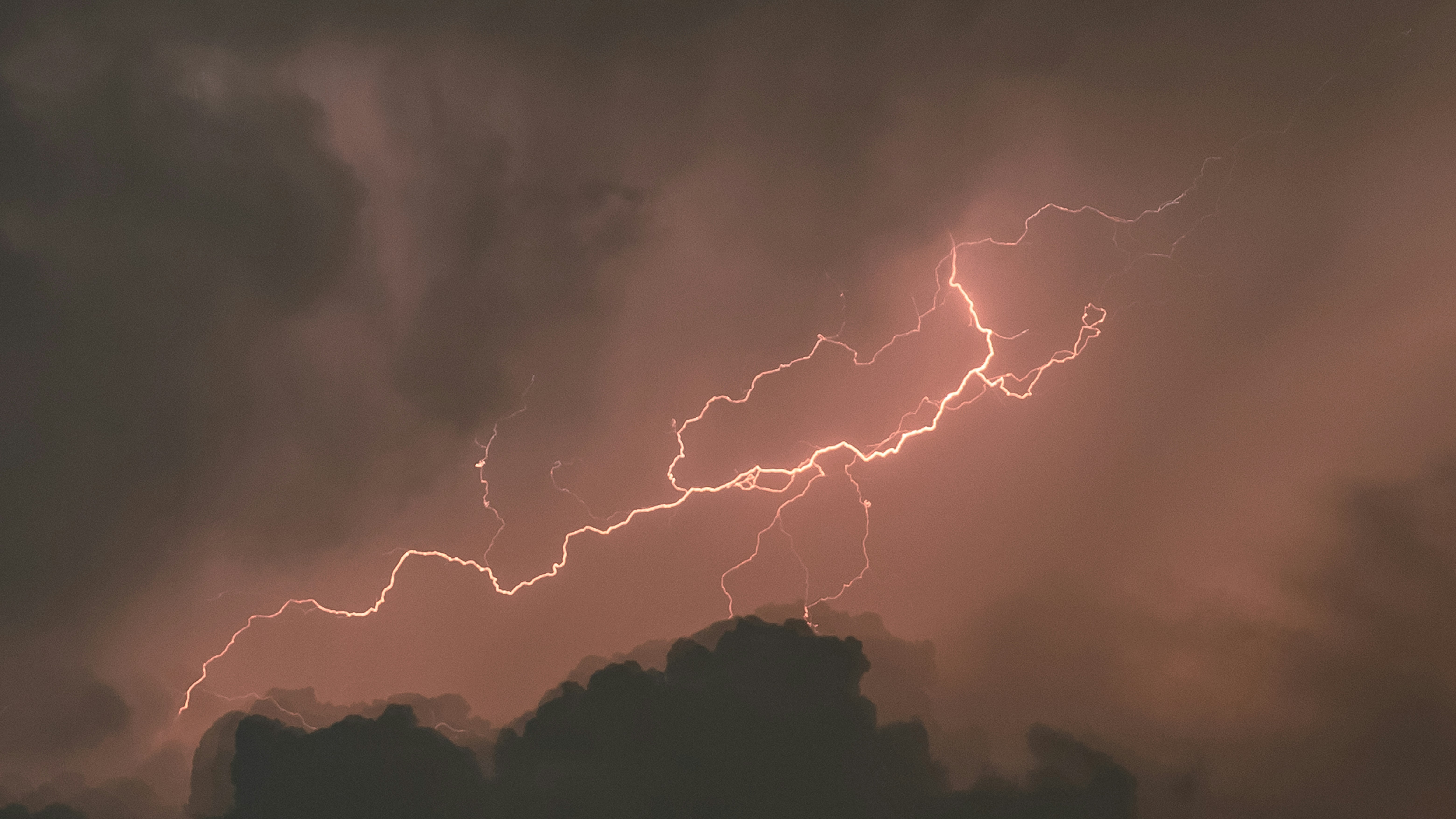 Dramatic lightning bolts illuminate dark storm clouds during a tempestuous evening.