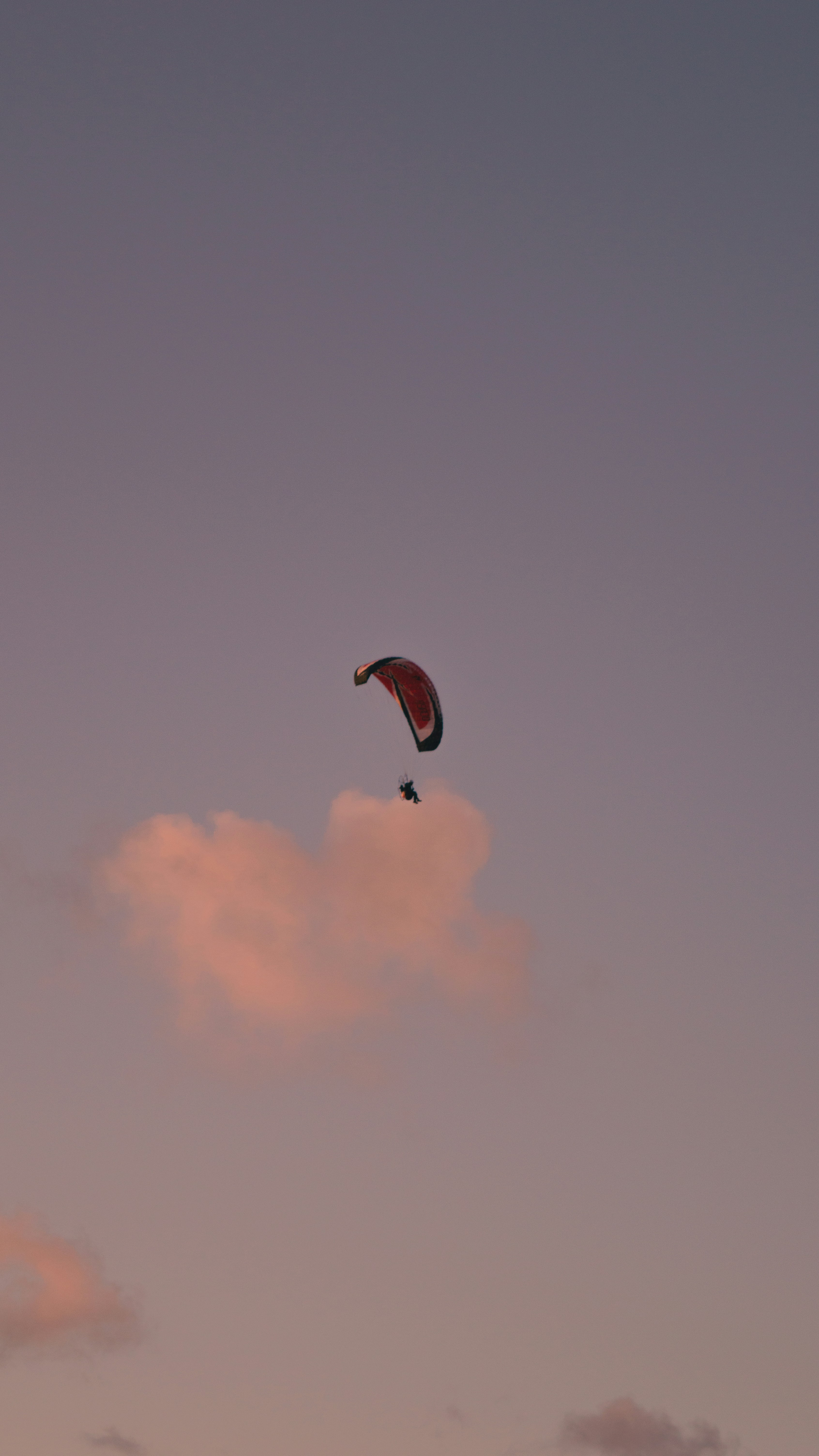 person in red parachute under cloudy sky during daytime