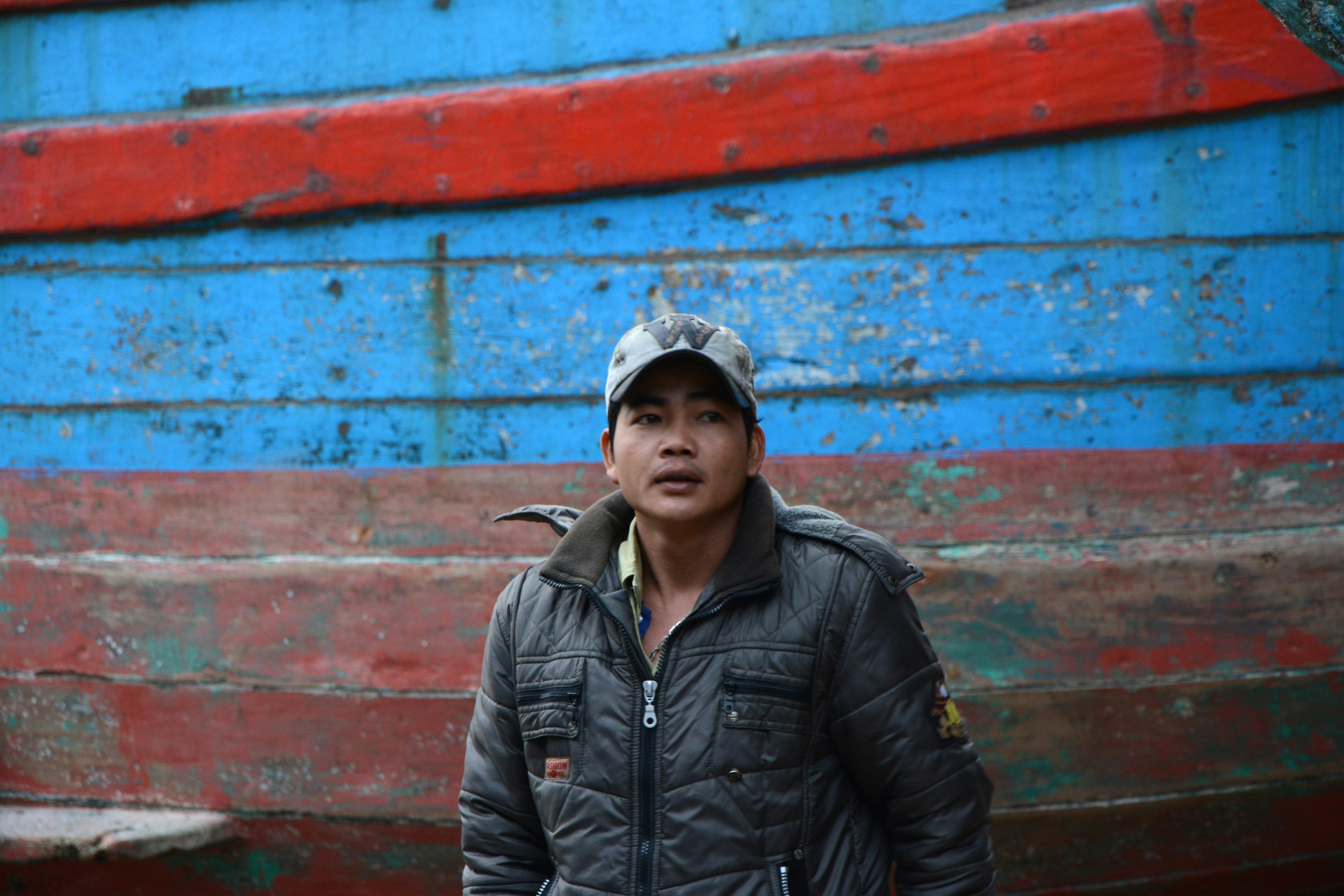 Portrait in Front of a Weathered Blue Boat Hull