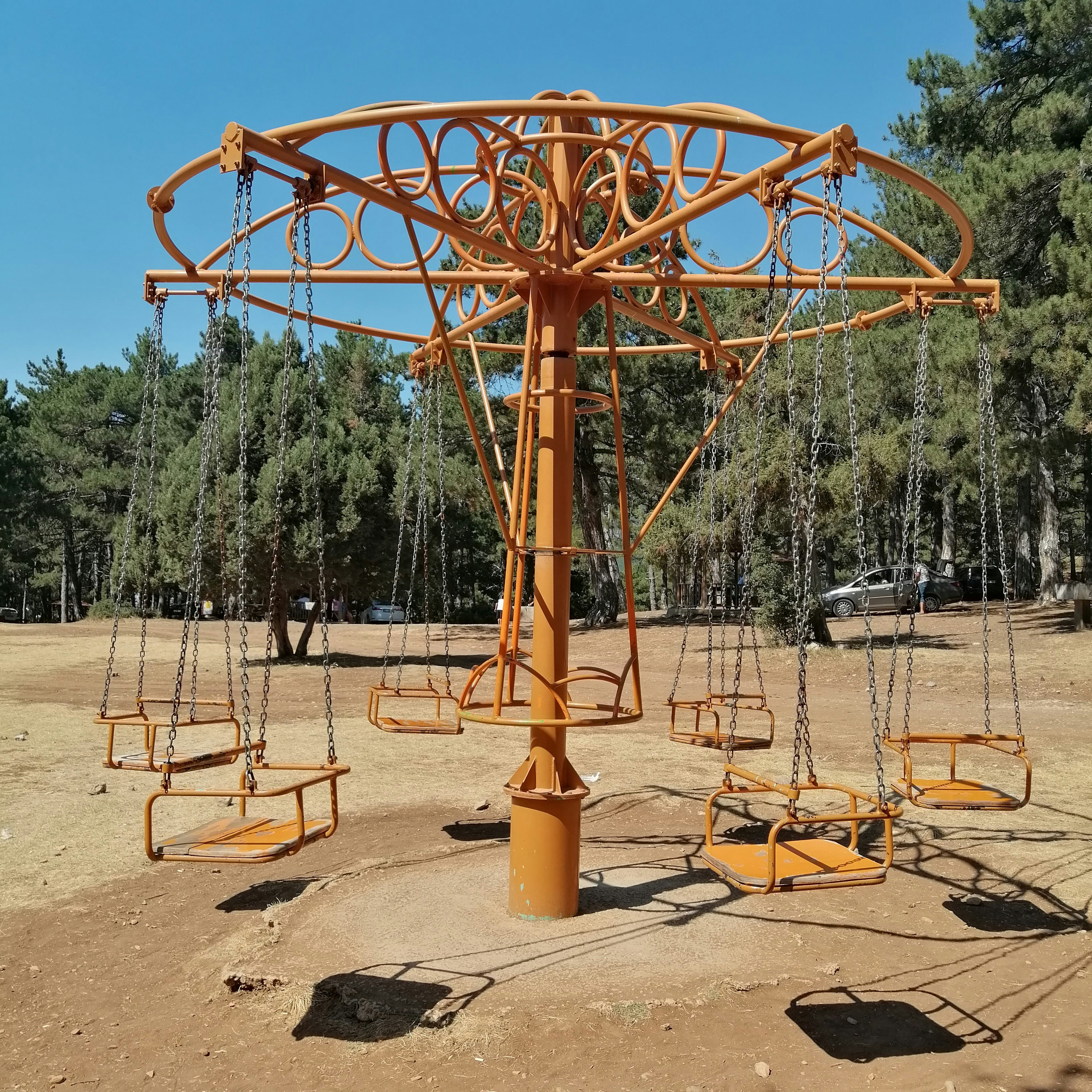Colorful swing carousel nestled among tall trees in a sunlit park, inviting playful nostalgia.