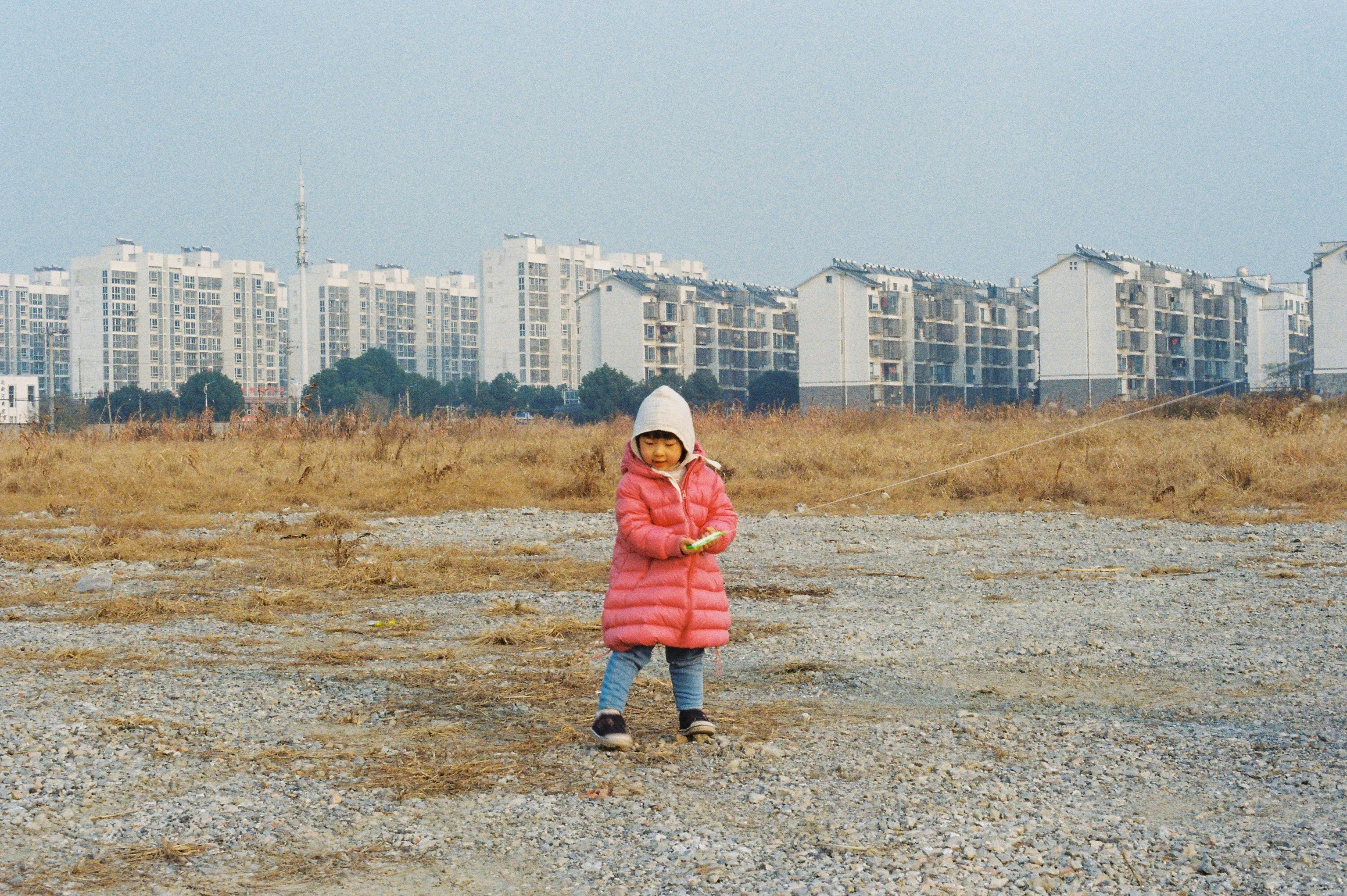 woman in red hoodie standing on gray sand during daytime