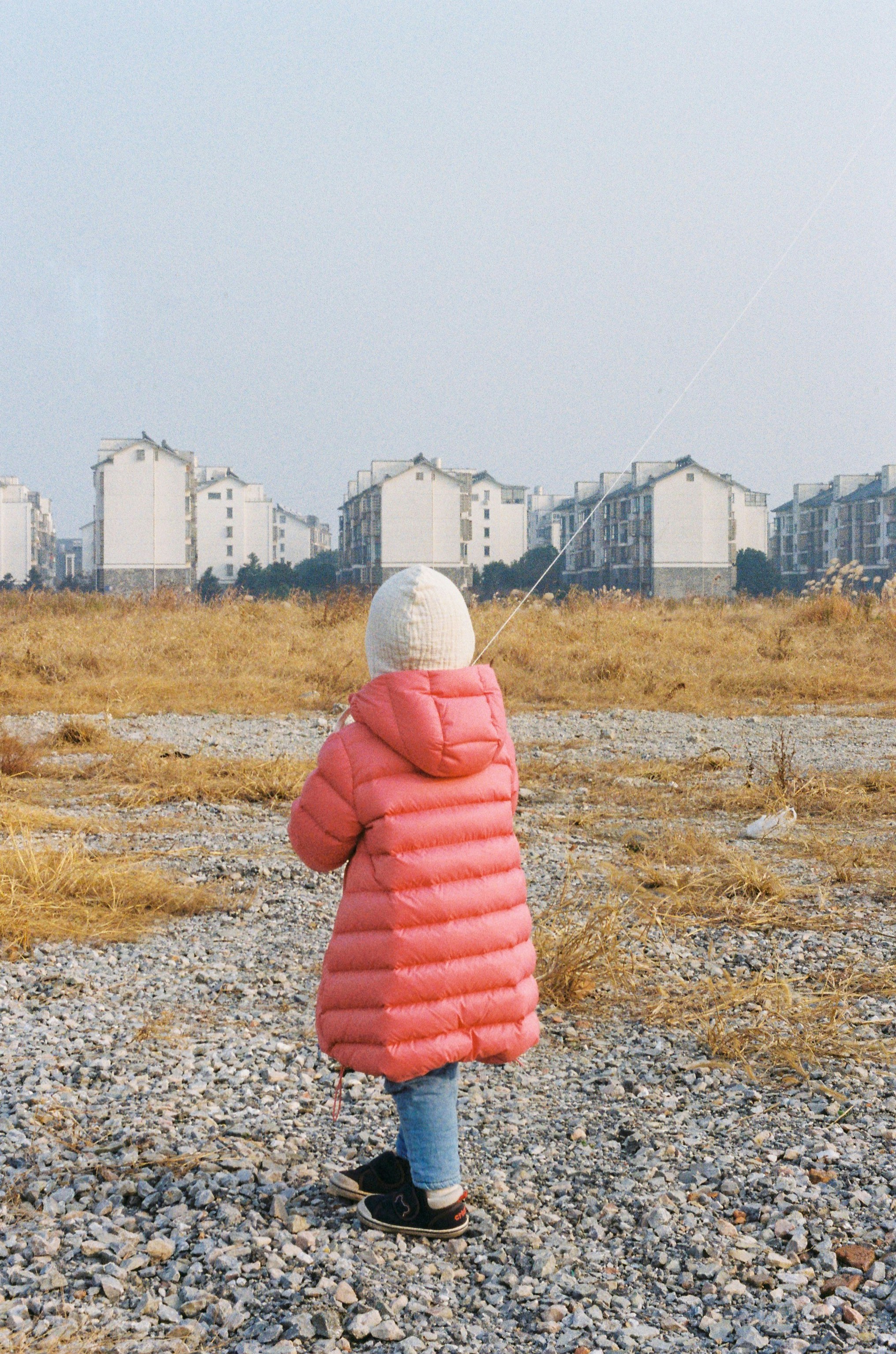 person in orange jacket sitting on ground during daytime
