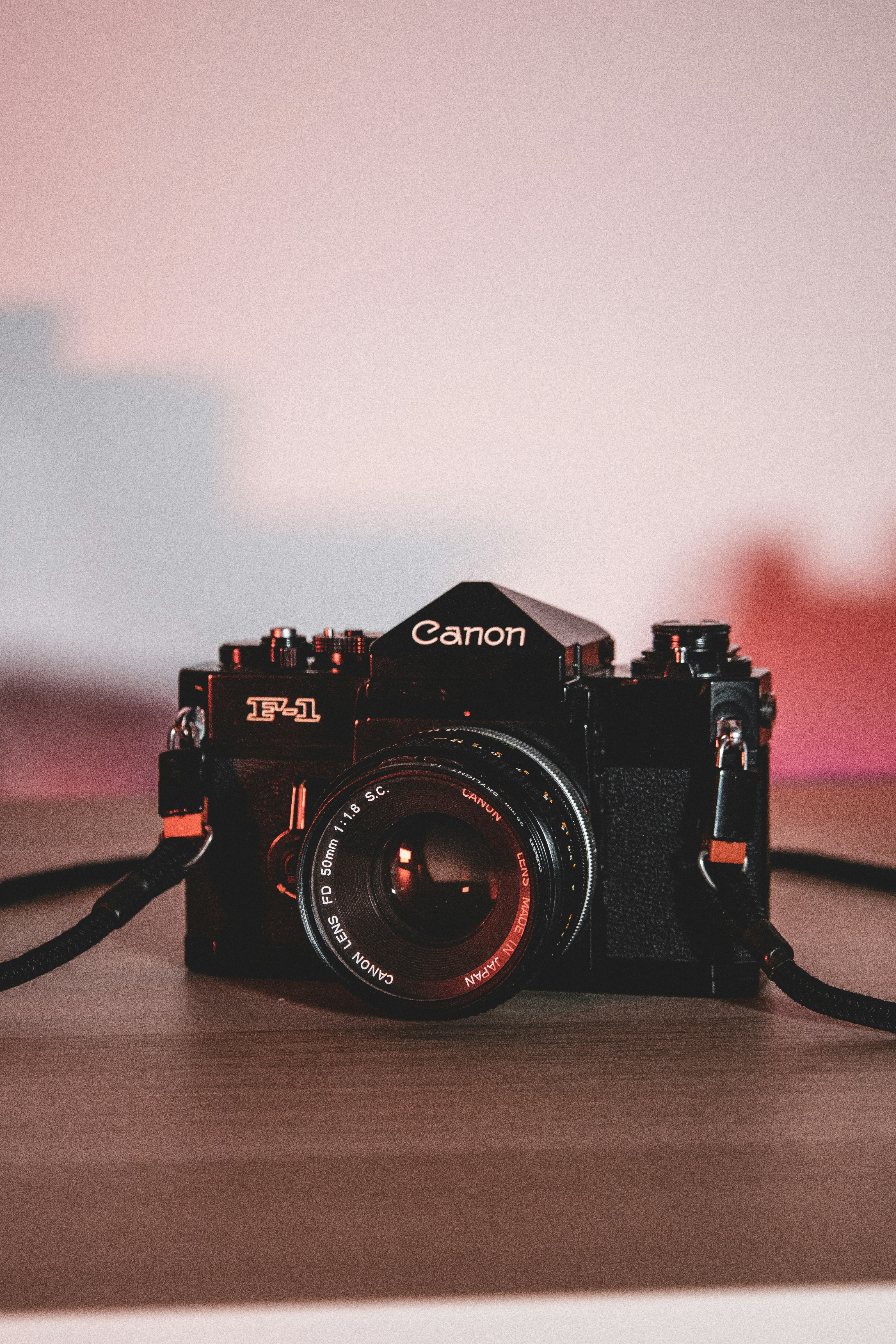Classic Canon F-1 camera positioned on a wooden surface, showcasing its vintage design against a softly blurred background.