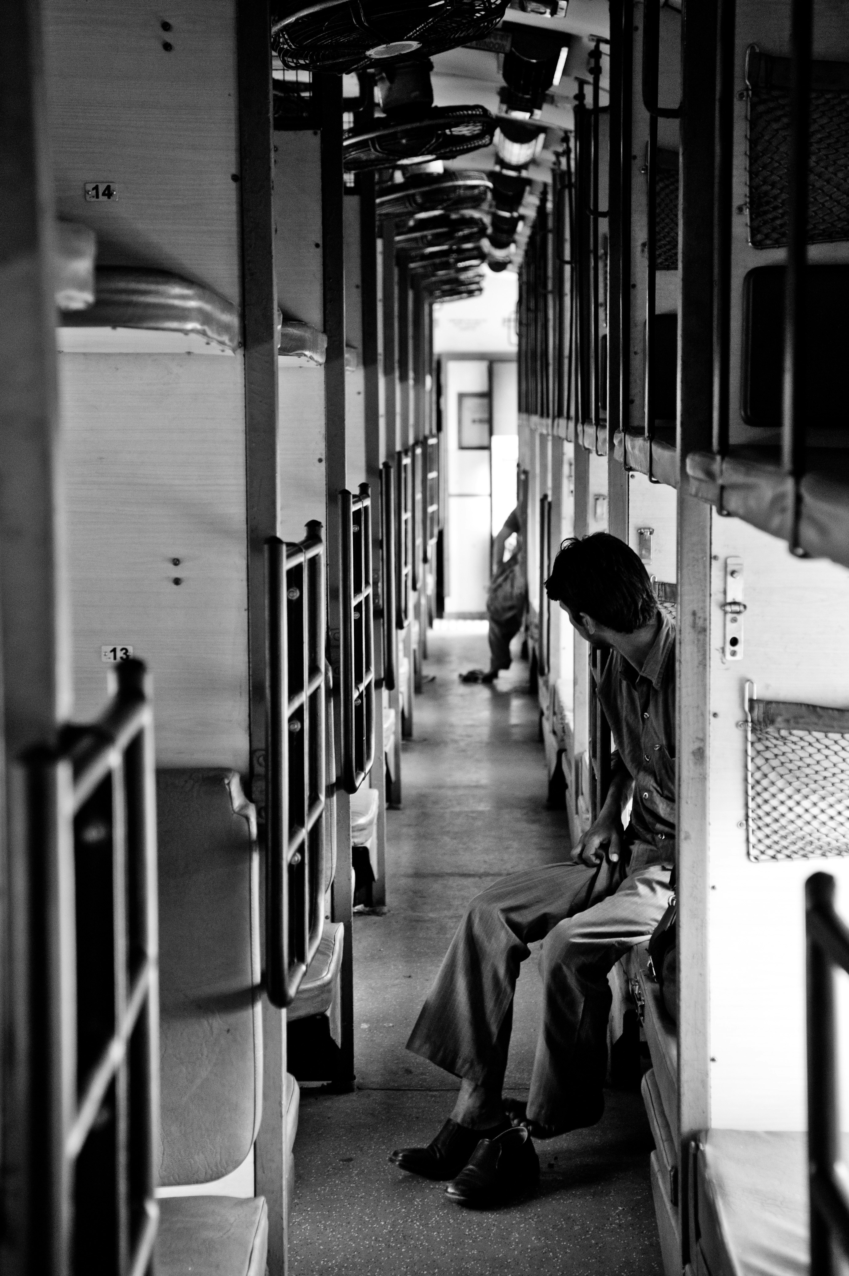 Interior of a train carriage with passengers seated in a monochrome setting, capturing the essence of travel and solitude.