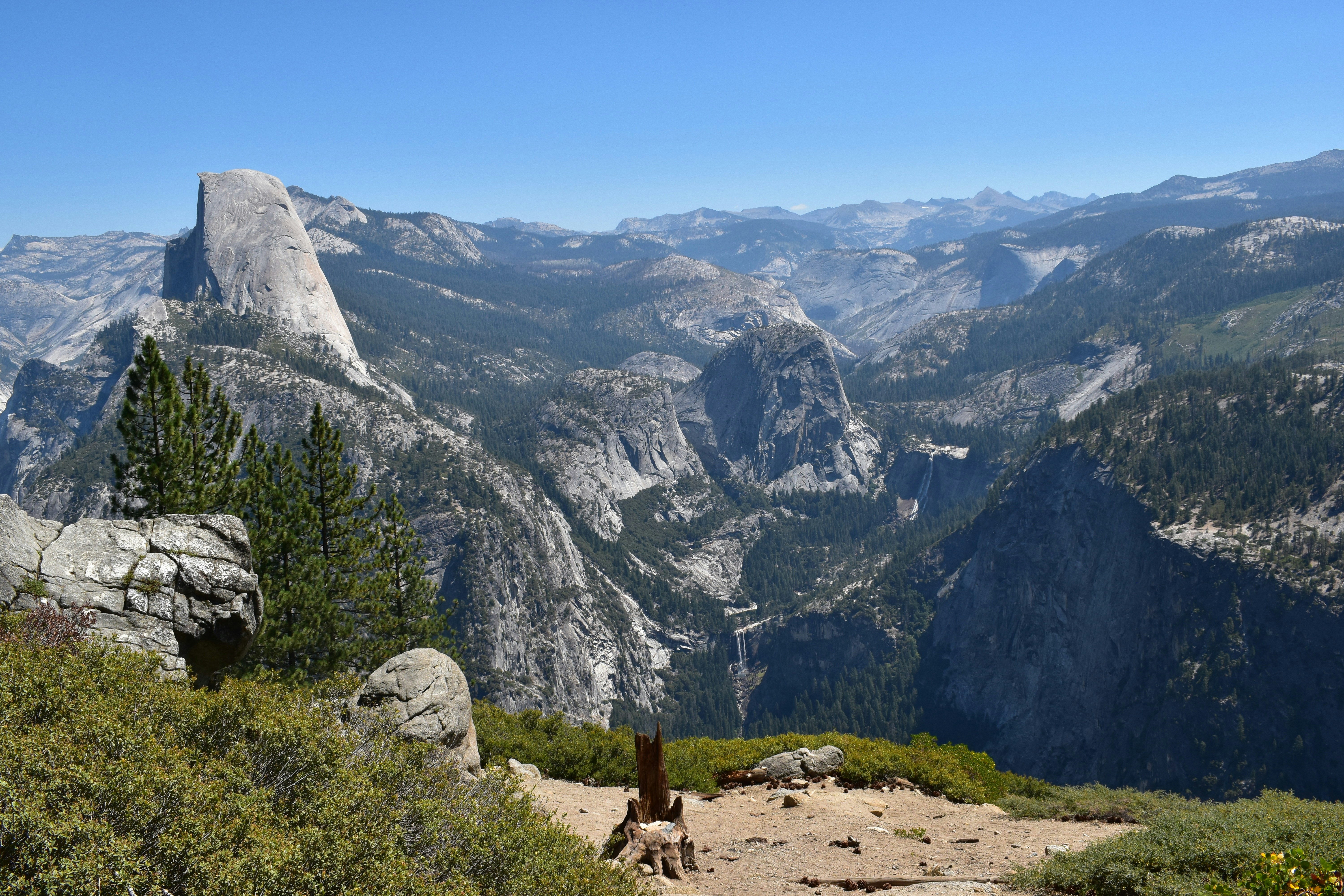 Vast landscape of Yosemite National Park showcasing towering granite formations and deep valleys under a clear blue sky.