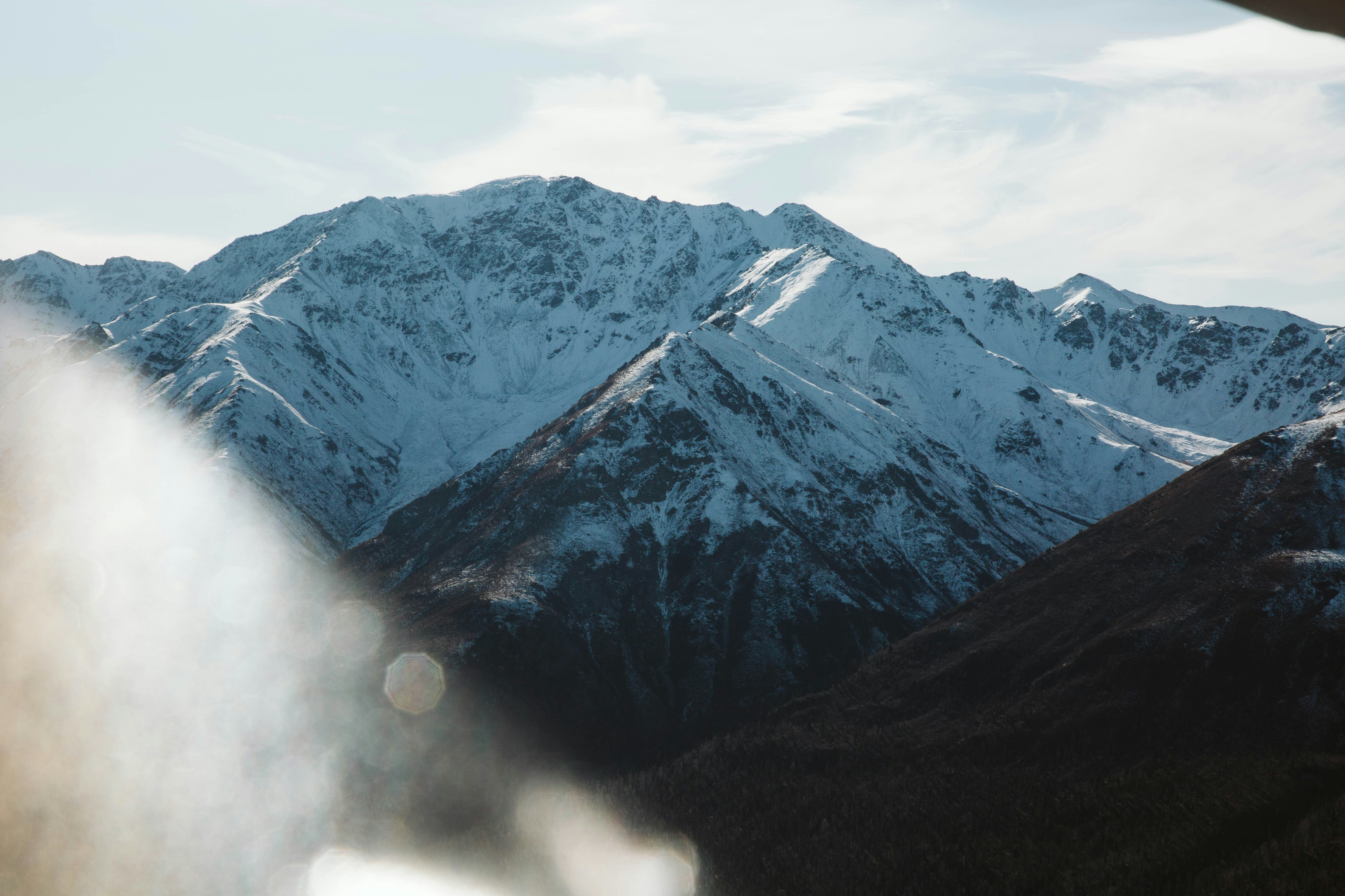 Snow-covered mountain range under a clear sky, showcasing rugged terrain and dramatic slopes.