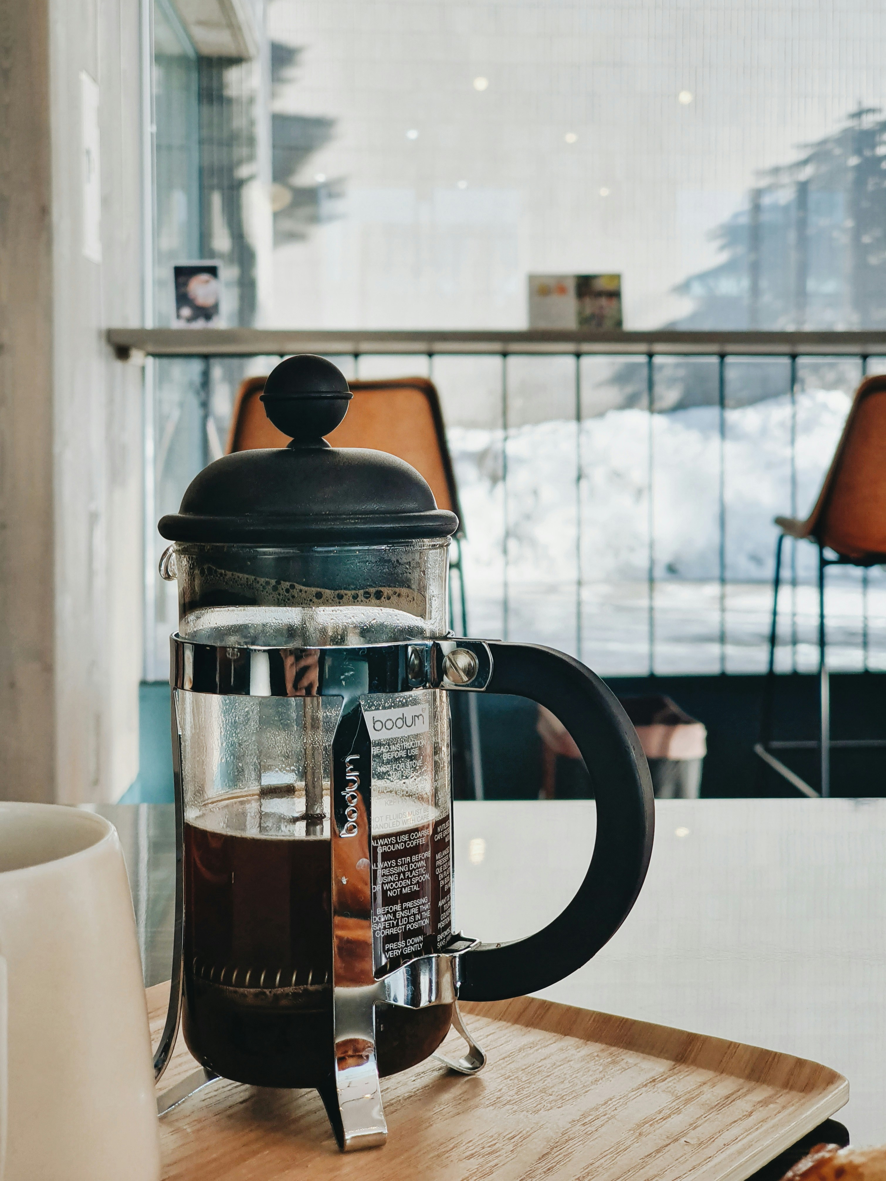Coffee prepared in a French press in a quiet cafe on a cold winter morning in Asahikawa, Hokkaido, Japan. | black and silver coffee press