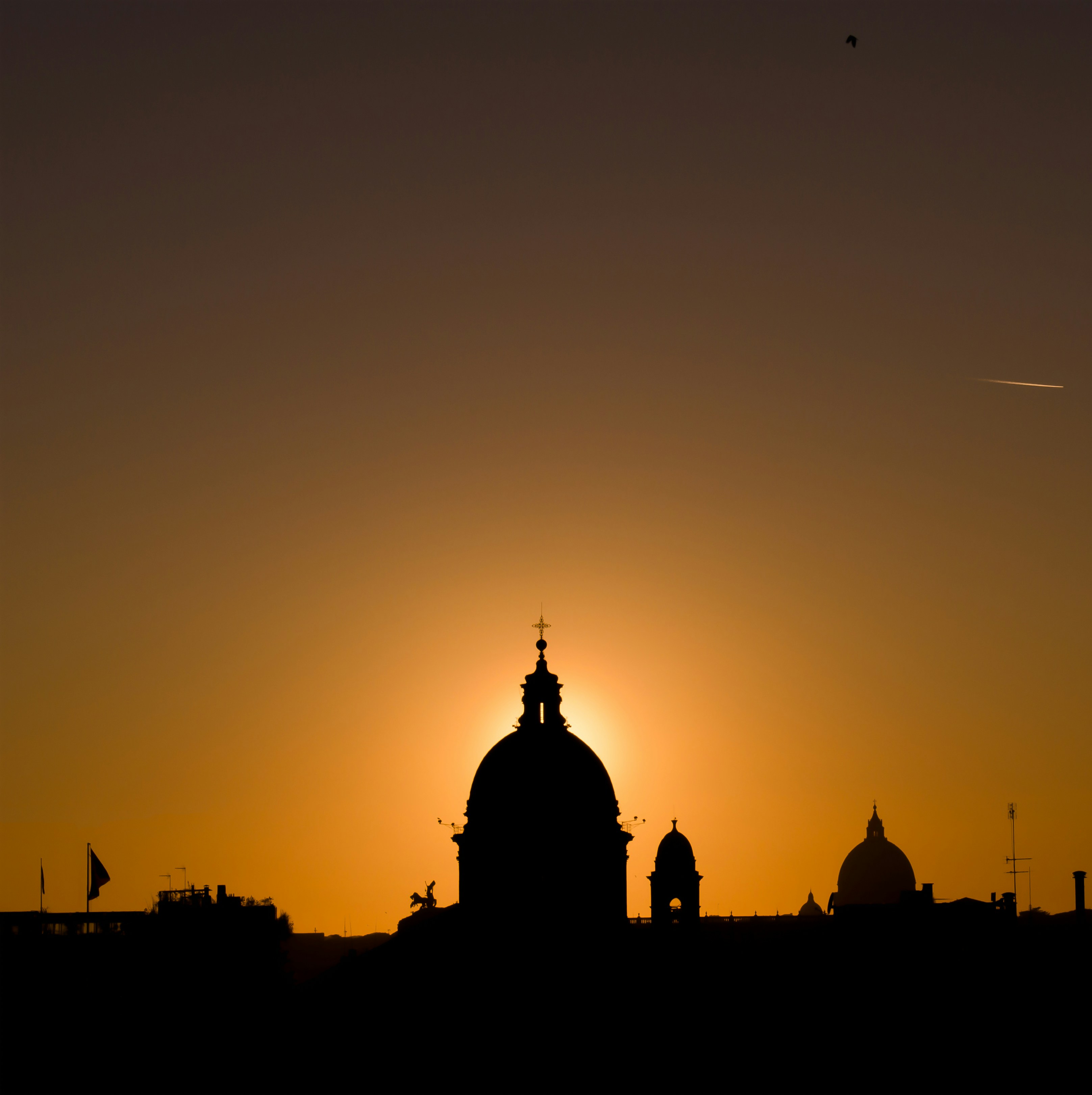 Historic city skyline silhouetted against a vibrant sunset, highlighting architectural features. 