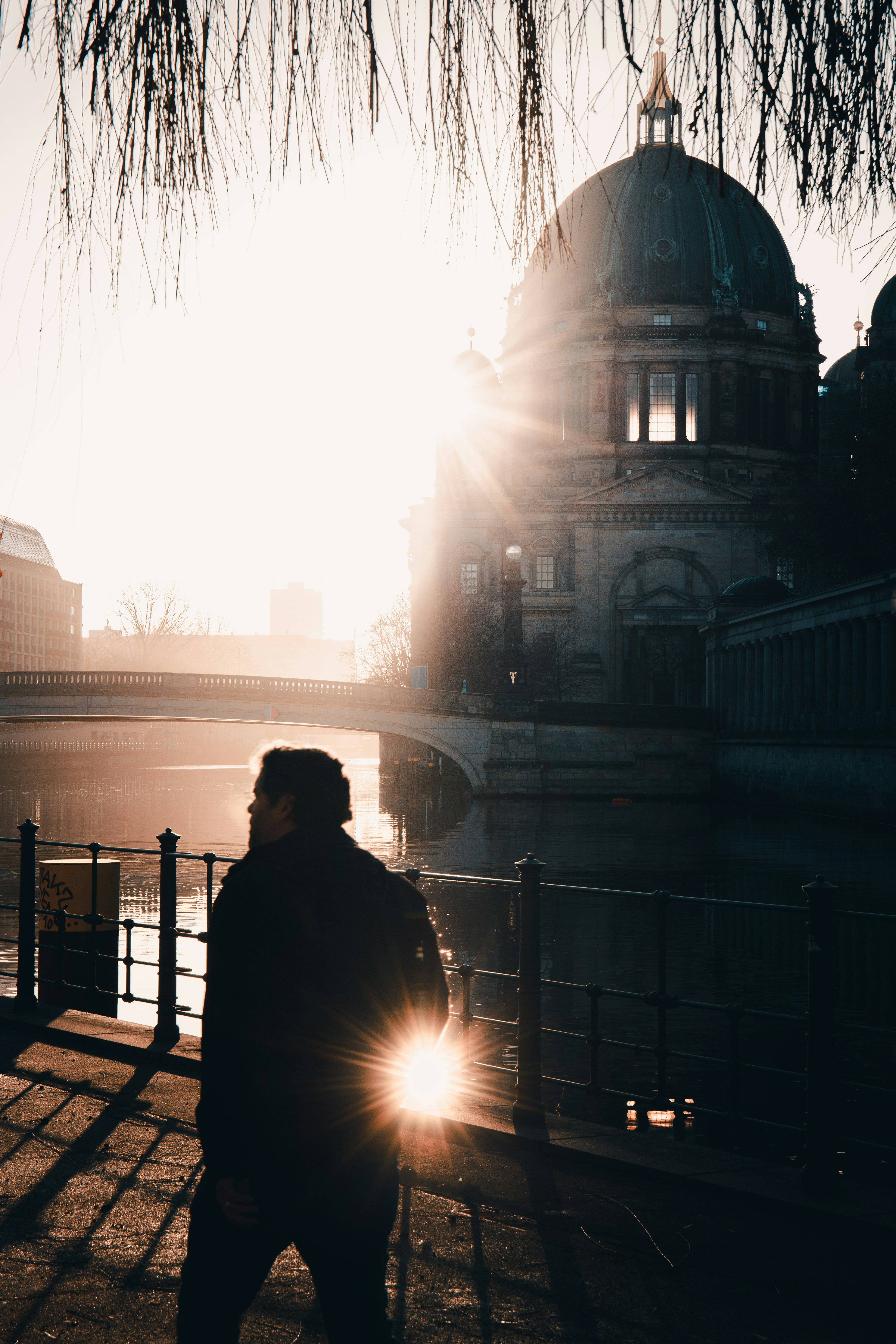 Sunburst Silhouette by the River: A Lone Figure Framed by a Domed City Hall