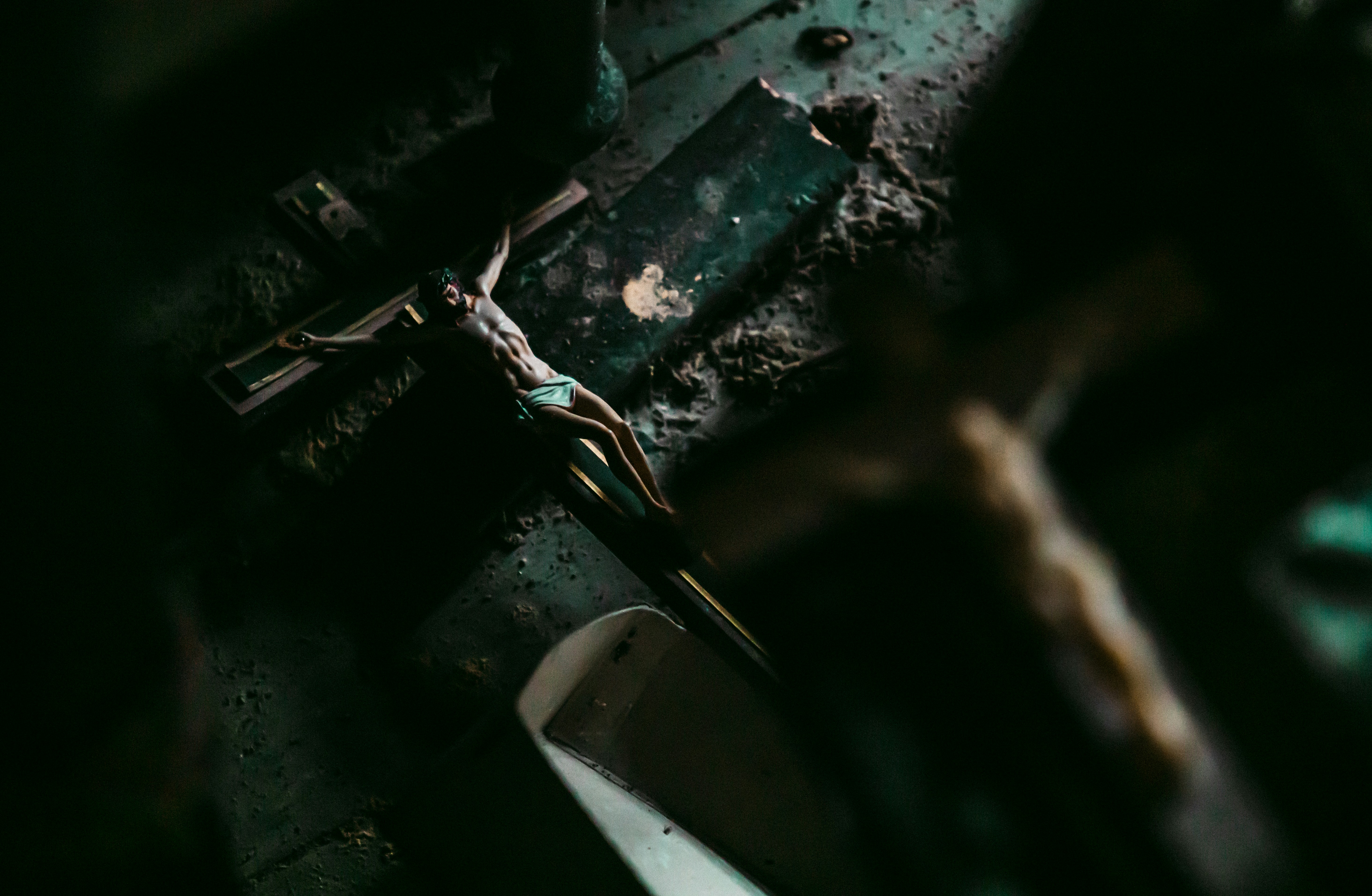 A detailed depiction of a crucifix, highlighting the intricate craftsmanship and somber atmosphere of an abandoned space. The interplay of light and shadow adds depth to the scene.