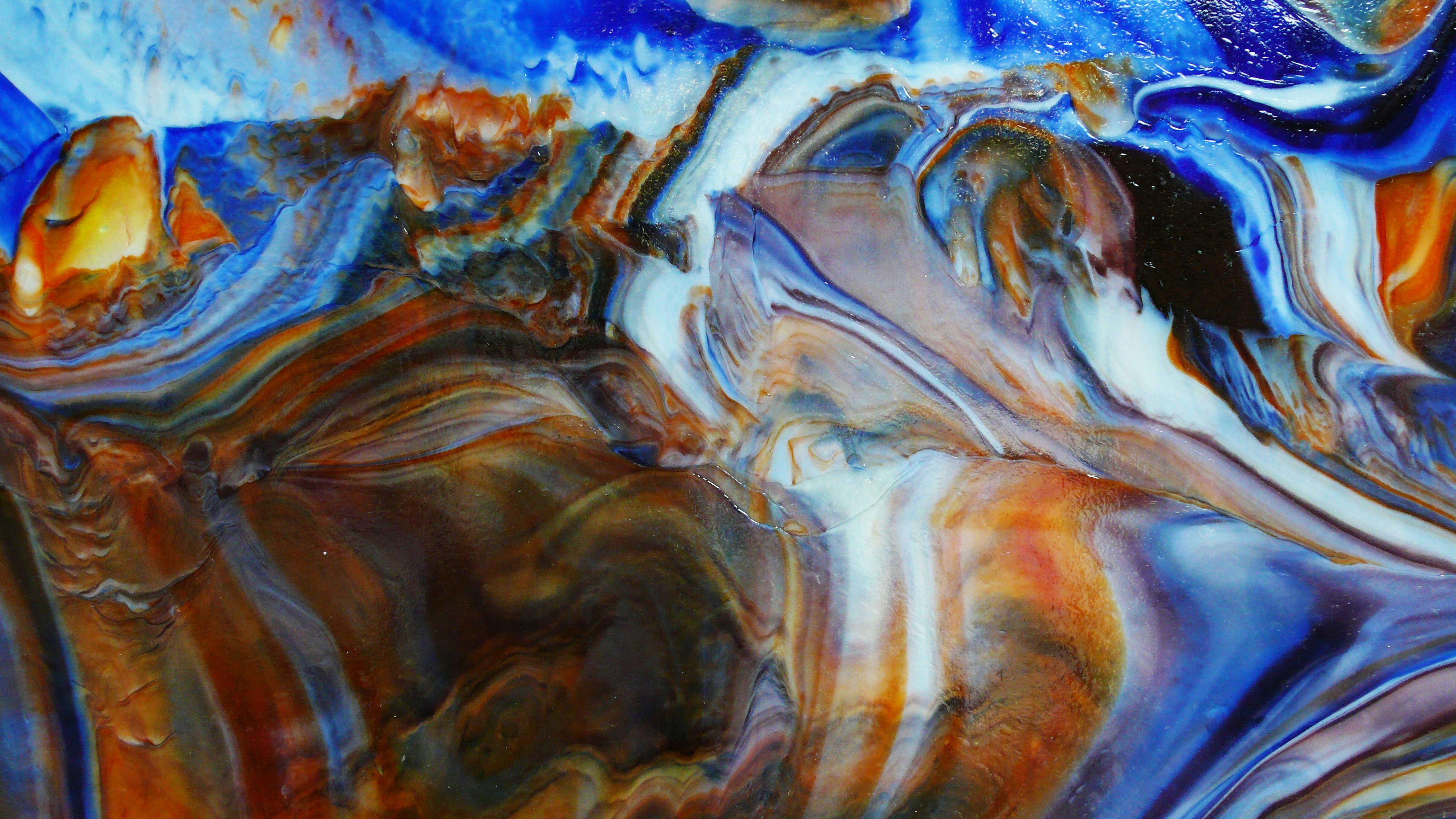 Abstract composition showcasing vibrant swirls of blue, orange, and brown, evoking the essence of natural landscapes. The fluid patterns create a mesmerizing visual experience.