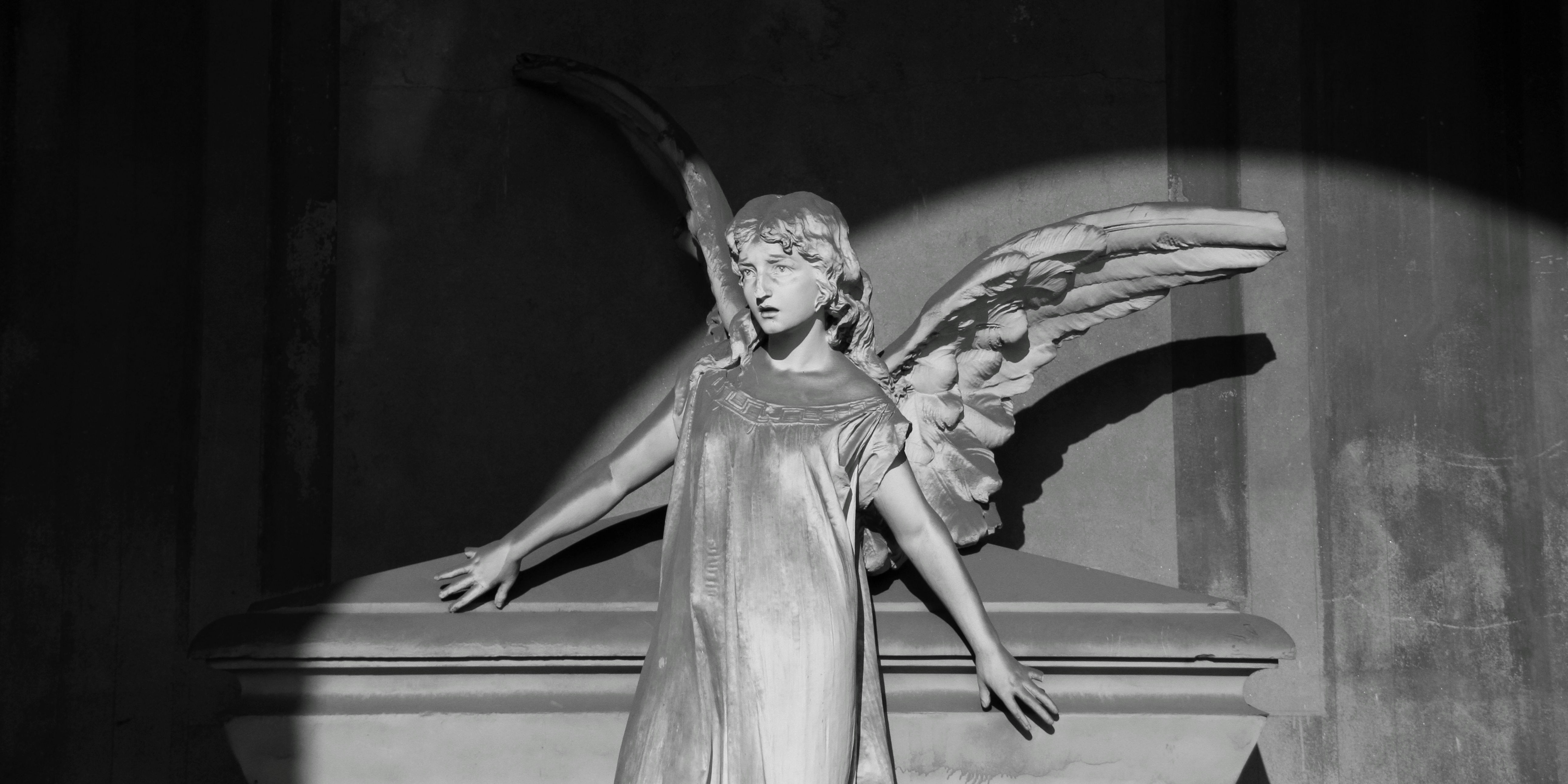 Spotlighted Angel on a Marble Pedestal Beneath a Halo of Shadow