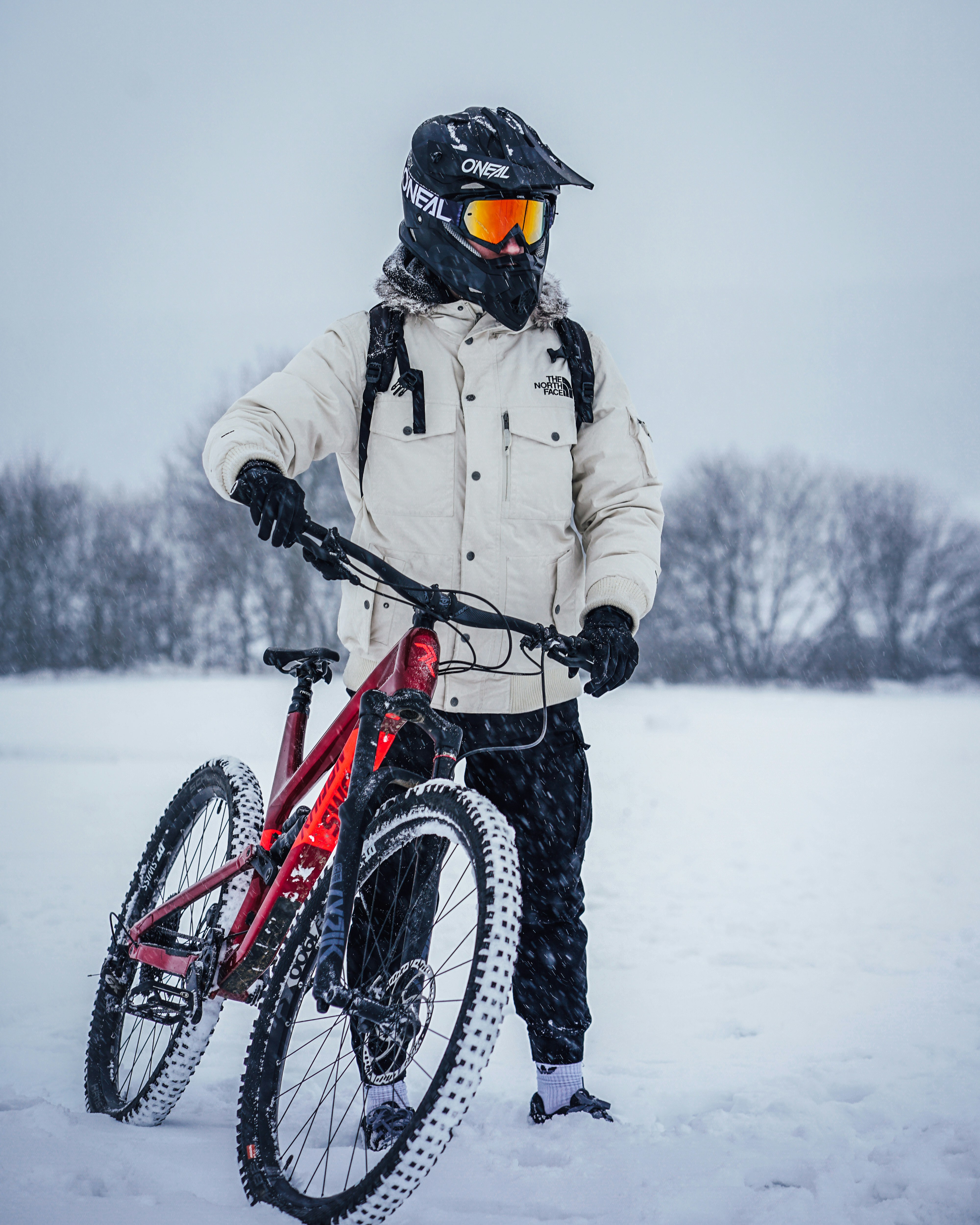 Man in white jacket riding red and black mountain bike on snow covered ...