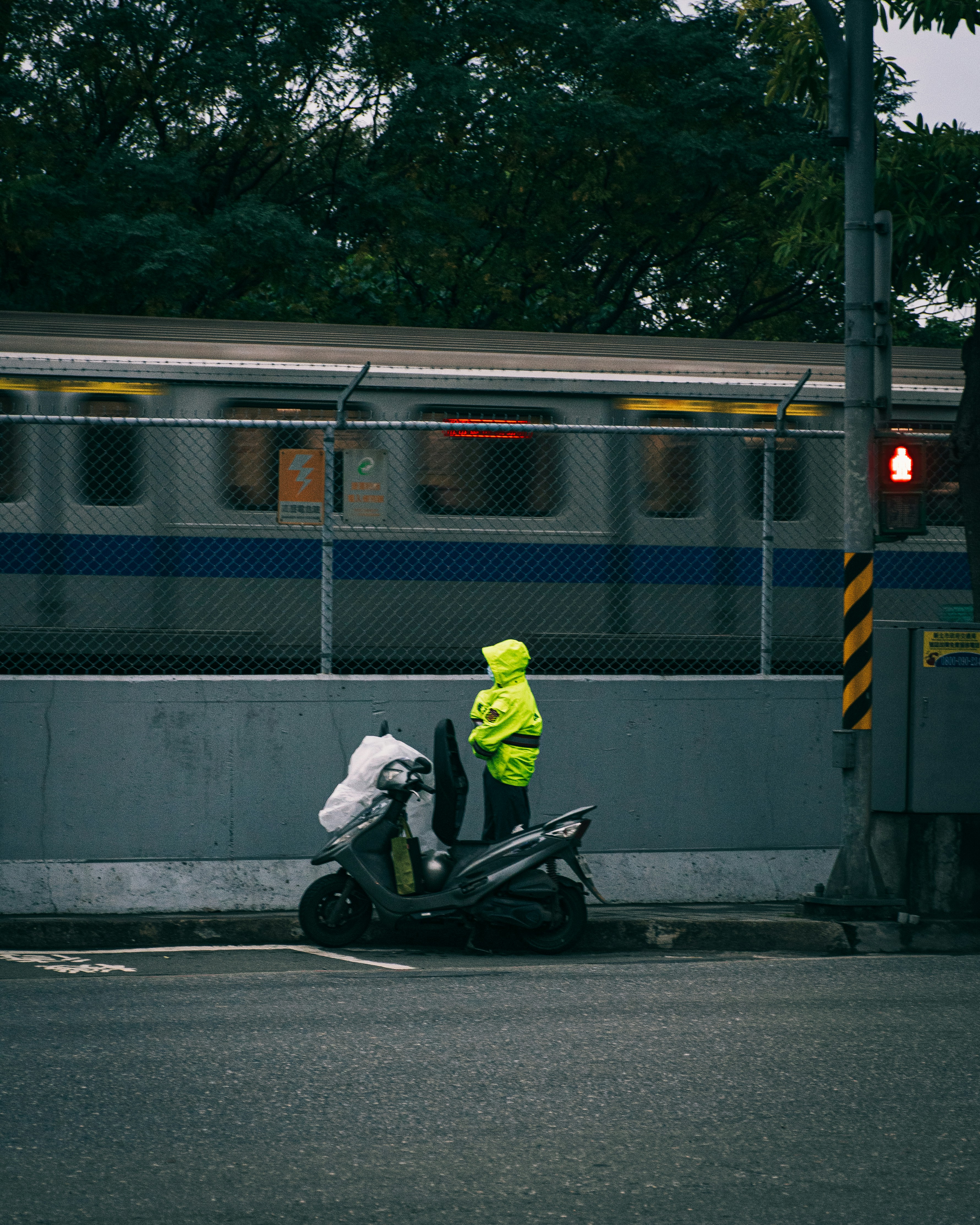 Neon Sentinel by the Rails: A Quiet Pause Behind the Fence