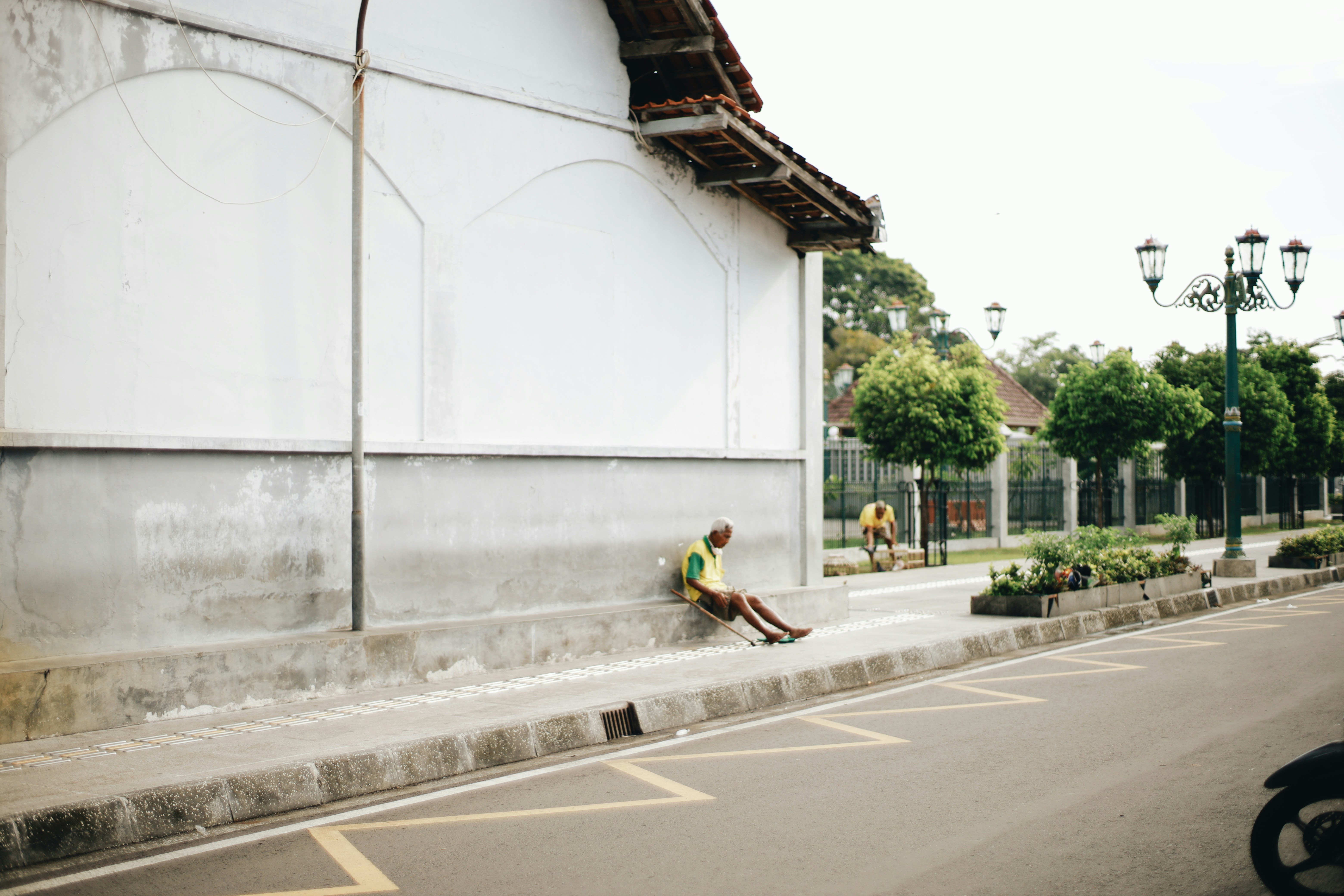 Curbside Solace Beneath a Weathered White Wall