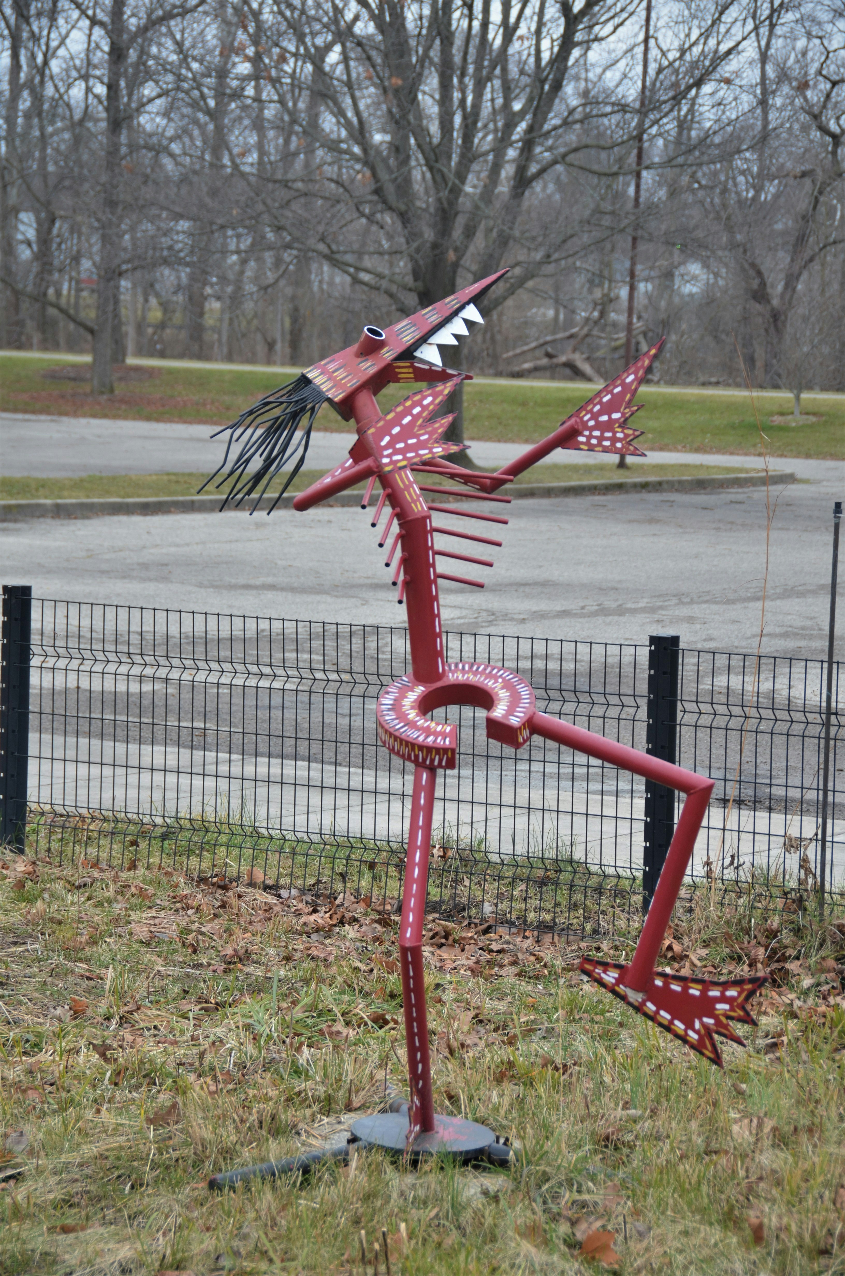 Red Steel Dragon Sculpture Guards a Quiet Park Fence