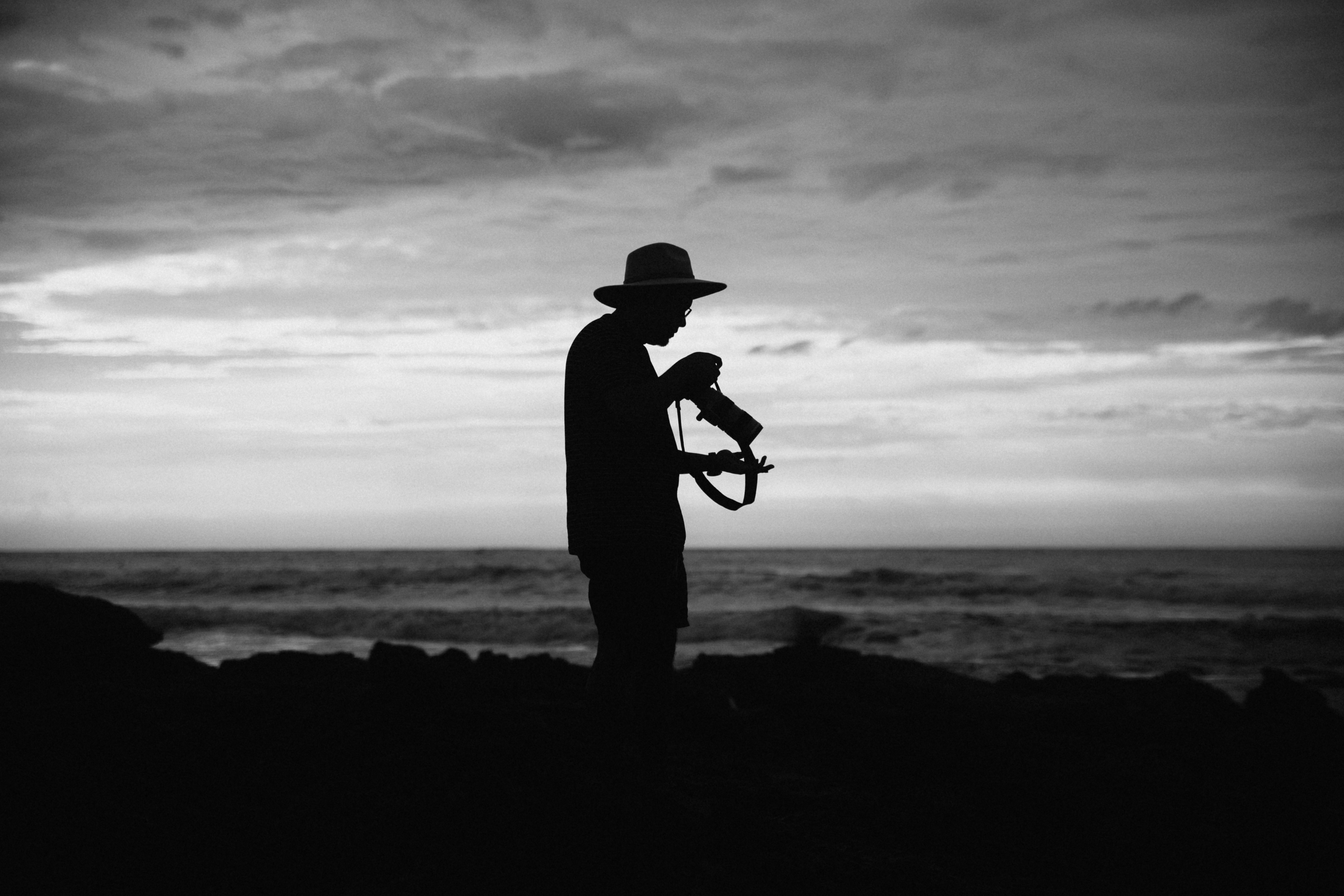 A silhouette of a photographer holding a camera against a dramatic coastal backdrop, emphasizing the connection between art and nature.