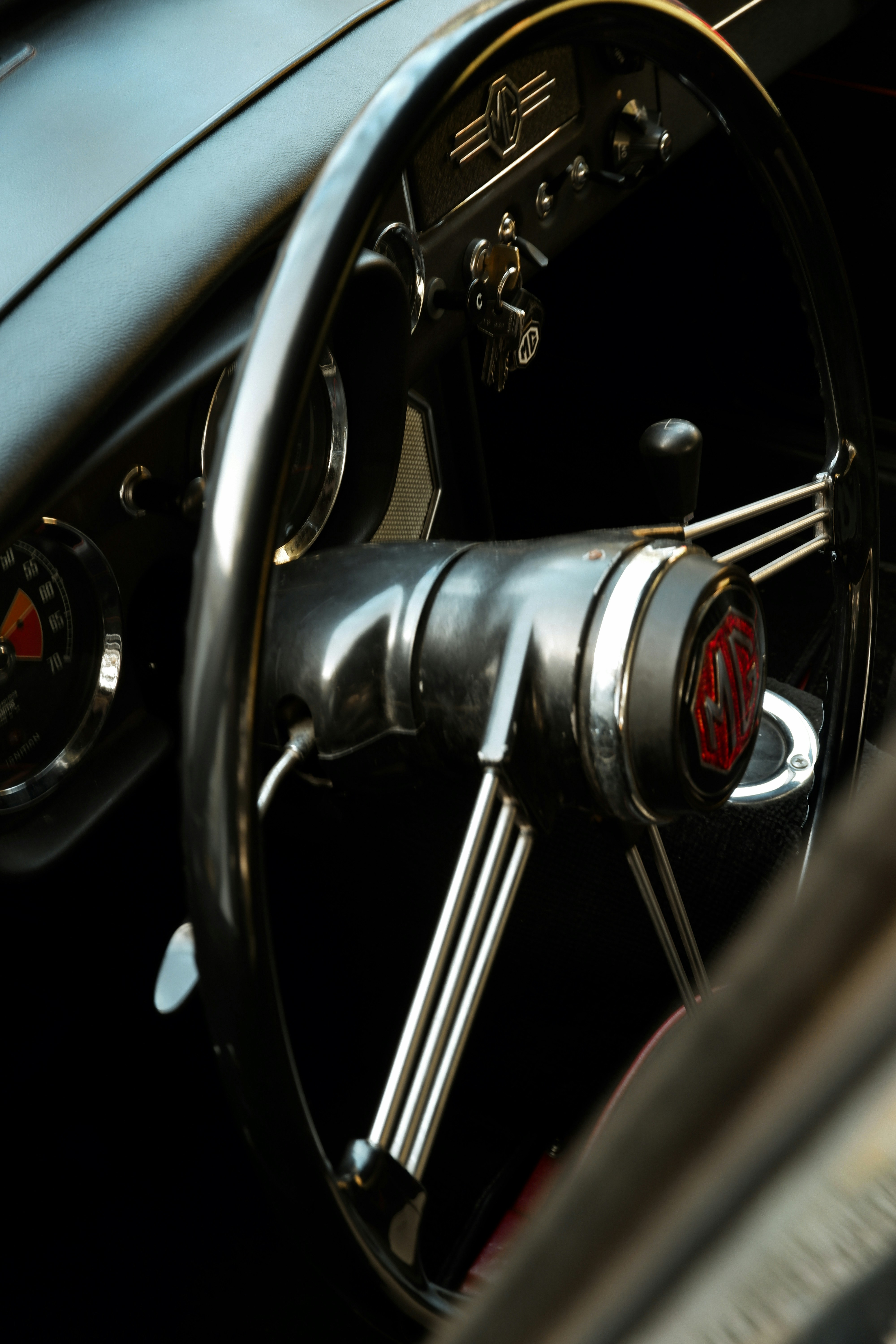 Close-up of a vintage MG car's steering wheel and dashboard, showcasing the intricate design and classic gauges.
