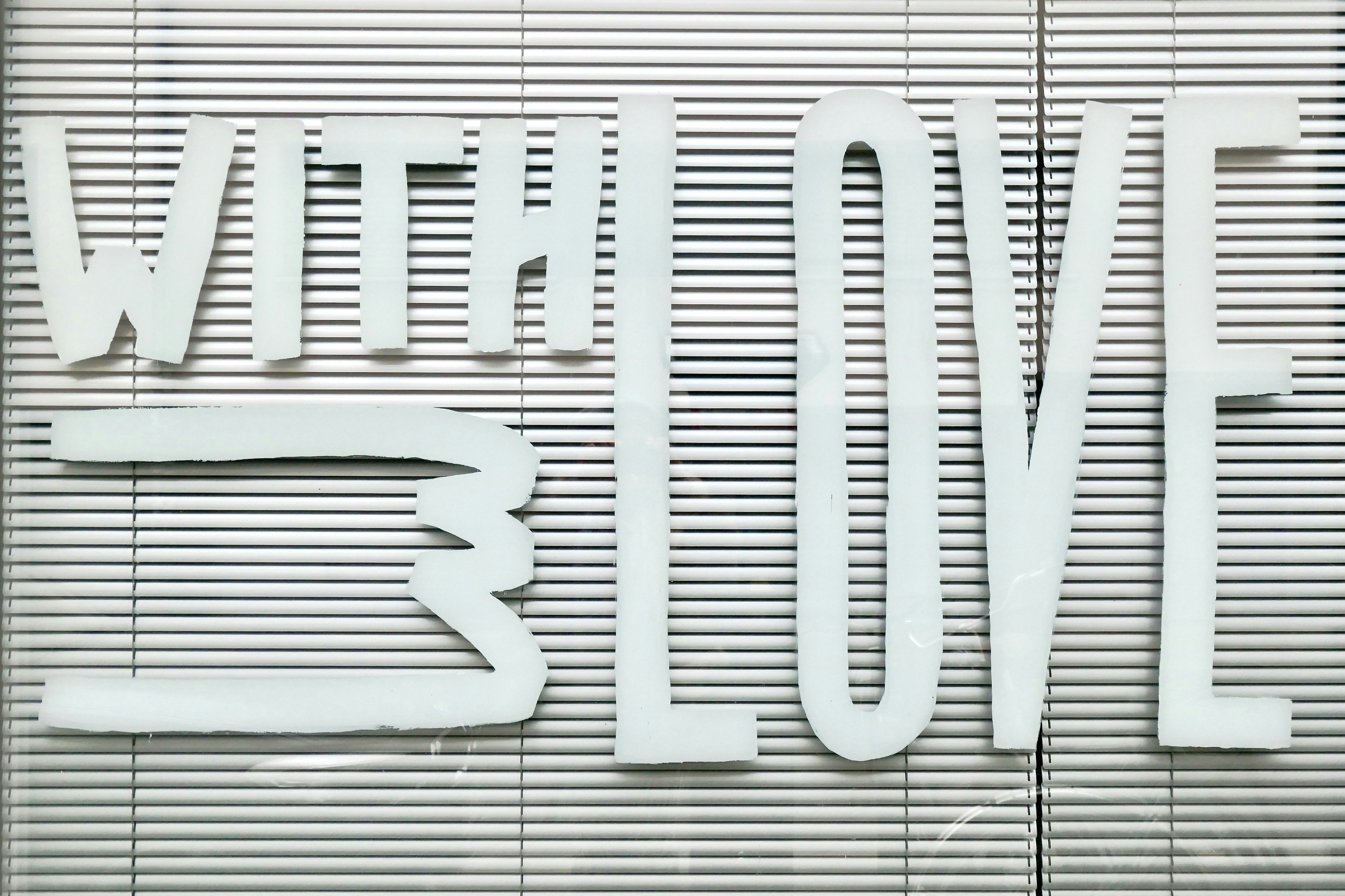 White lettering on a window reads 'WITH LOVE,' accompanied by a stylized fork design. The composition emphasizes a heartfelt connection to food.