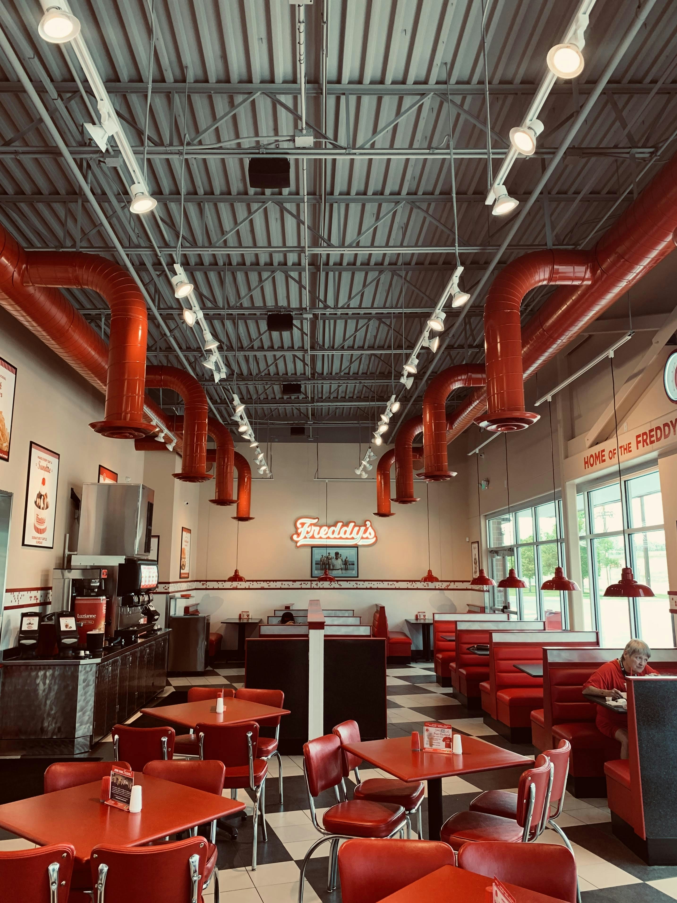 Vibrant interior of a Freddy's restaurant showcasing red booths and checkered floors, inviting patrons to enjoy a nostalgic meal.