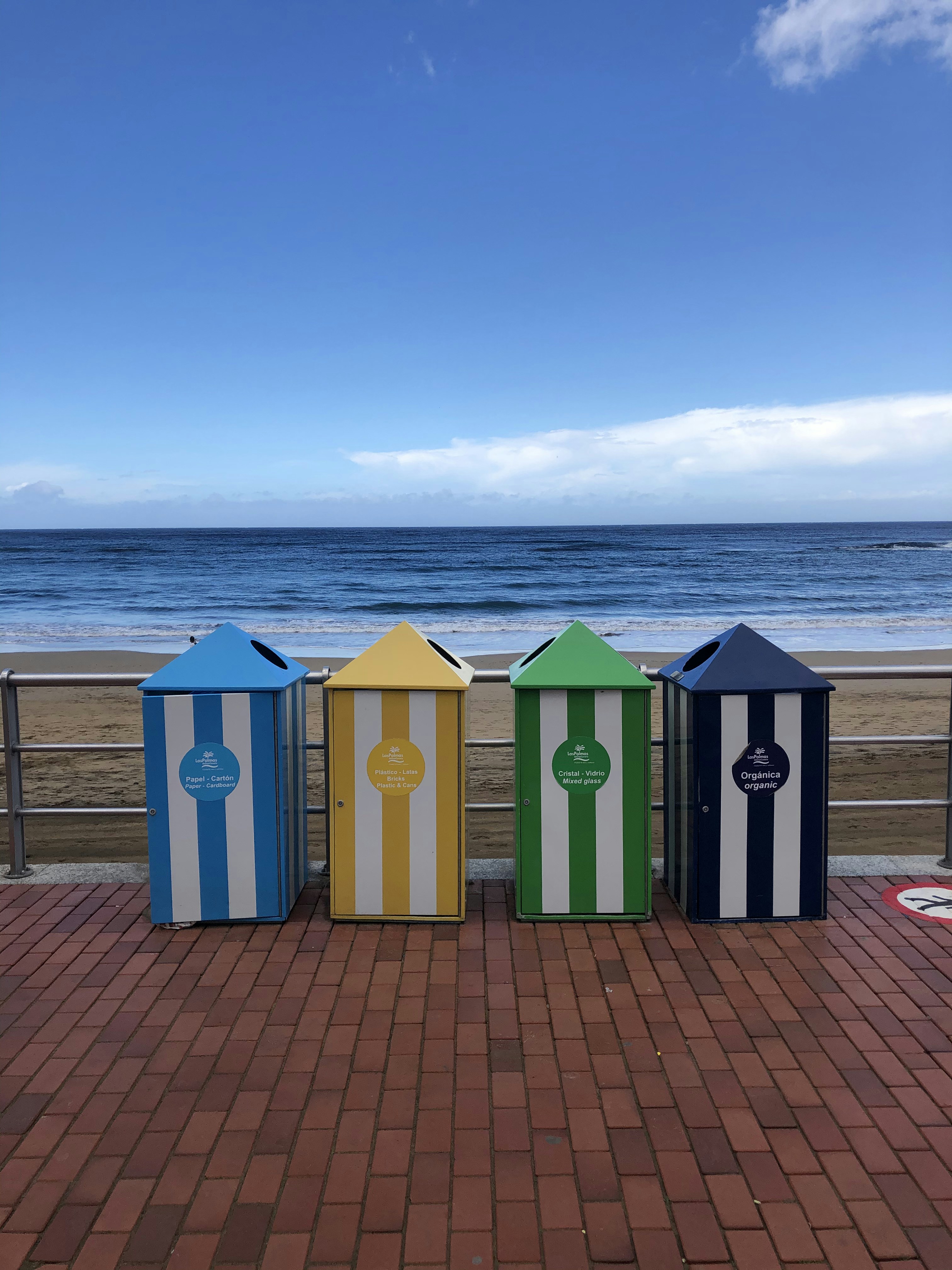 Color-Blocked Bins Line a Calm Beachfront Boardwalk