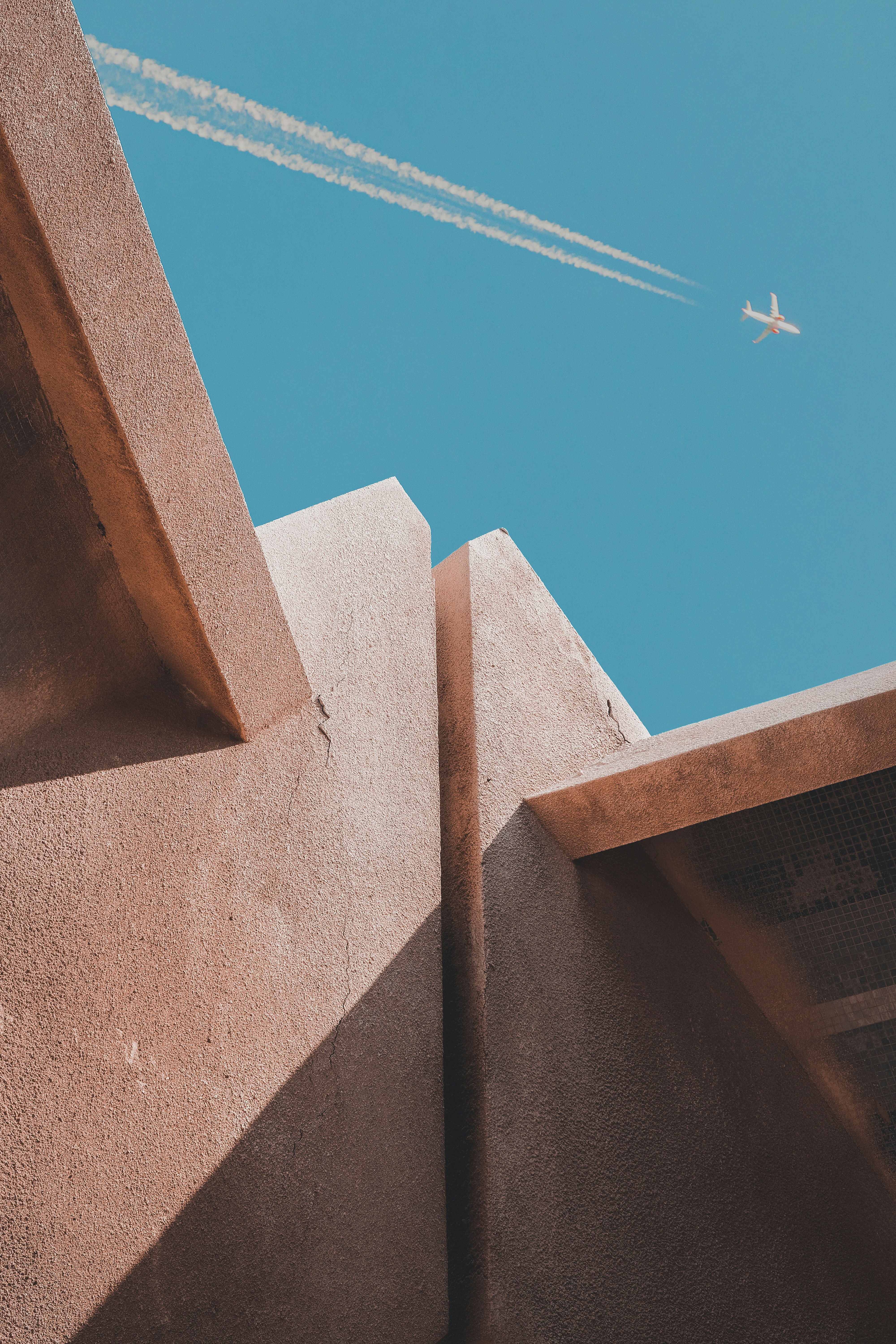 Terracotta Angles Beneath a Jet Trail