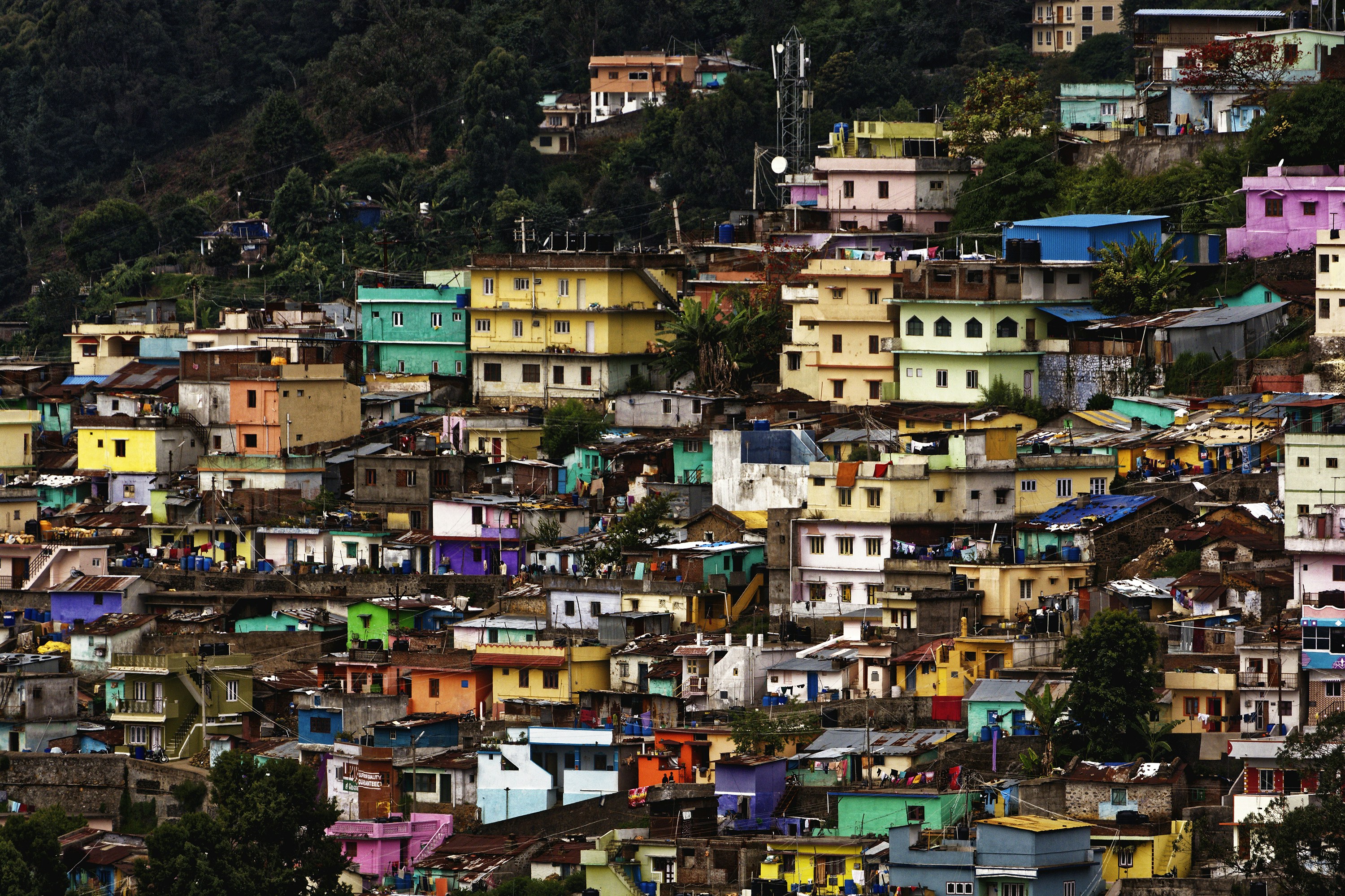 Colorful hillside homes stacked in a densely populated area, showcasing a blend of architectural styles and vibrant hues.