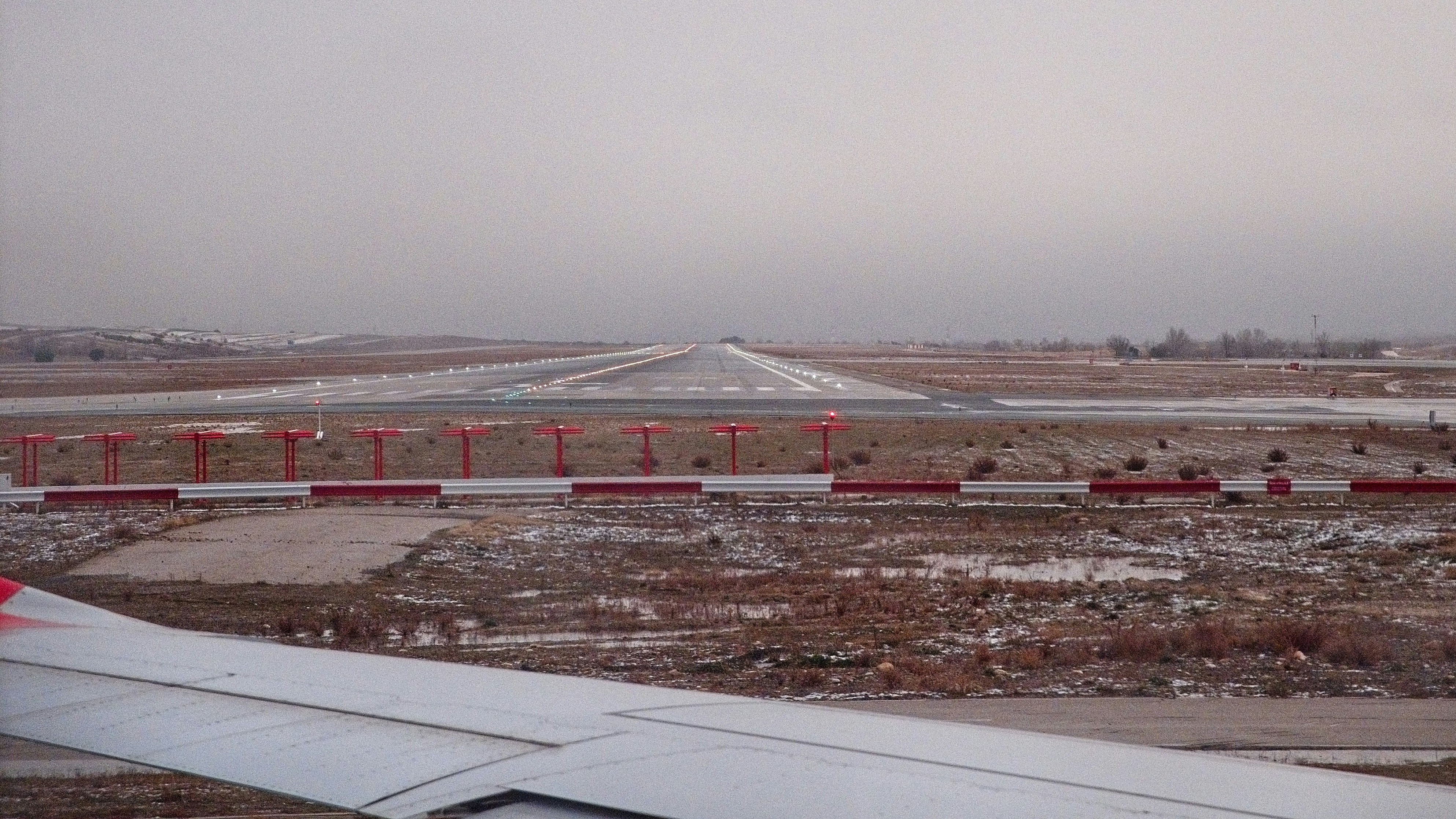 Winter Runway: Wing, Barriers, and a Distant Vanishing Point