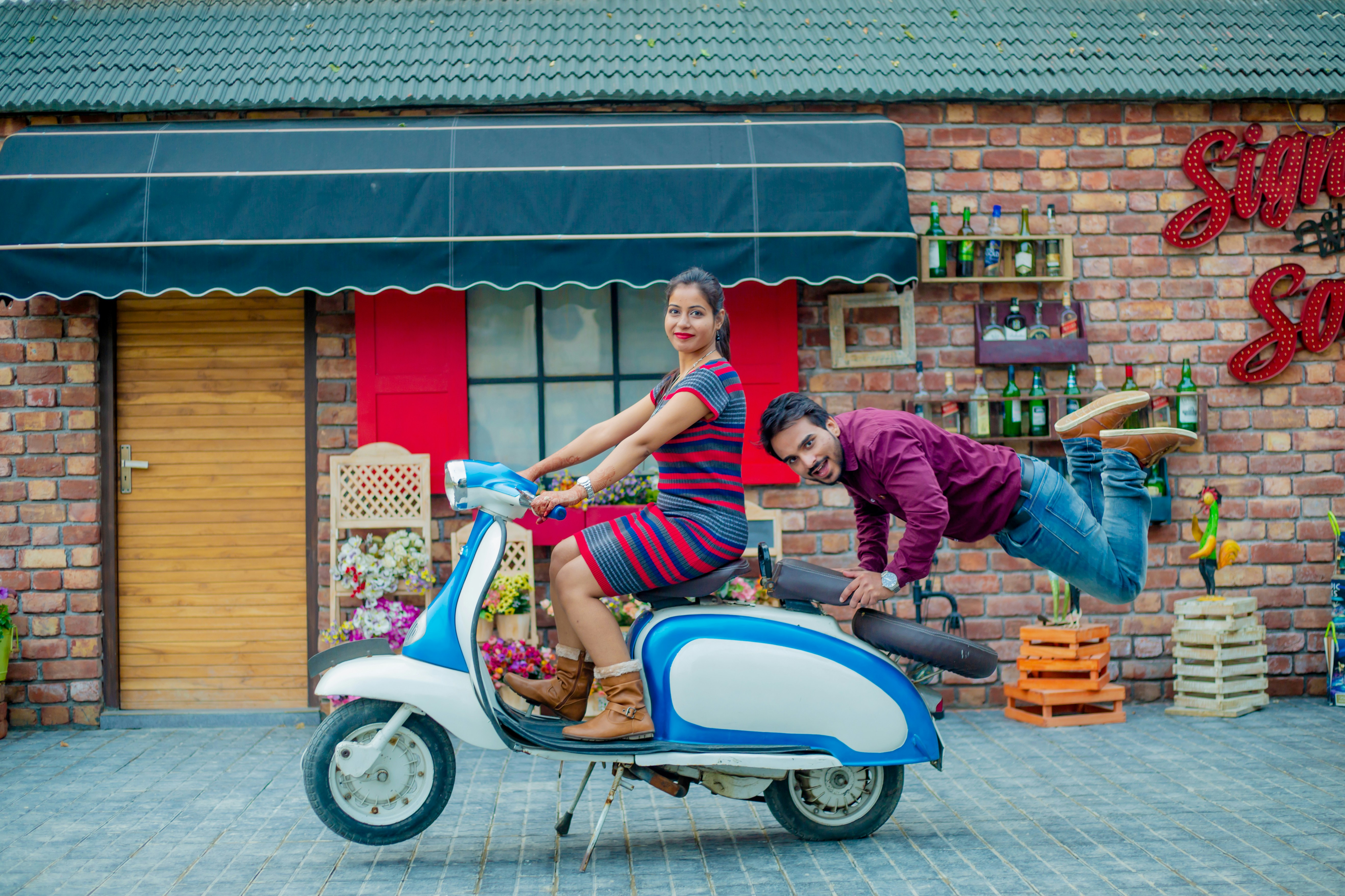 Playful Pivot on a Retro Blue Scooter Before a Brick storefront