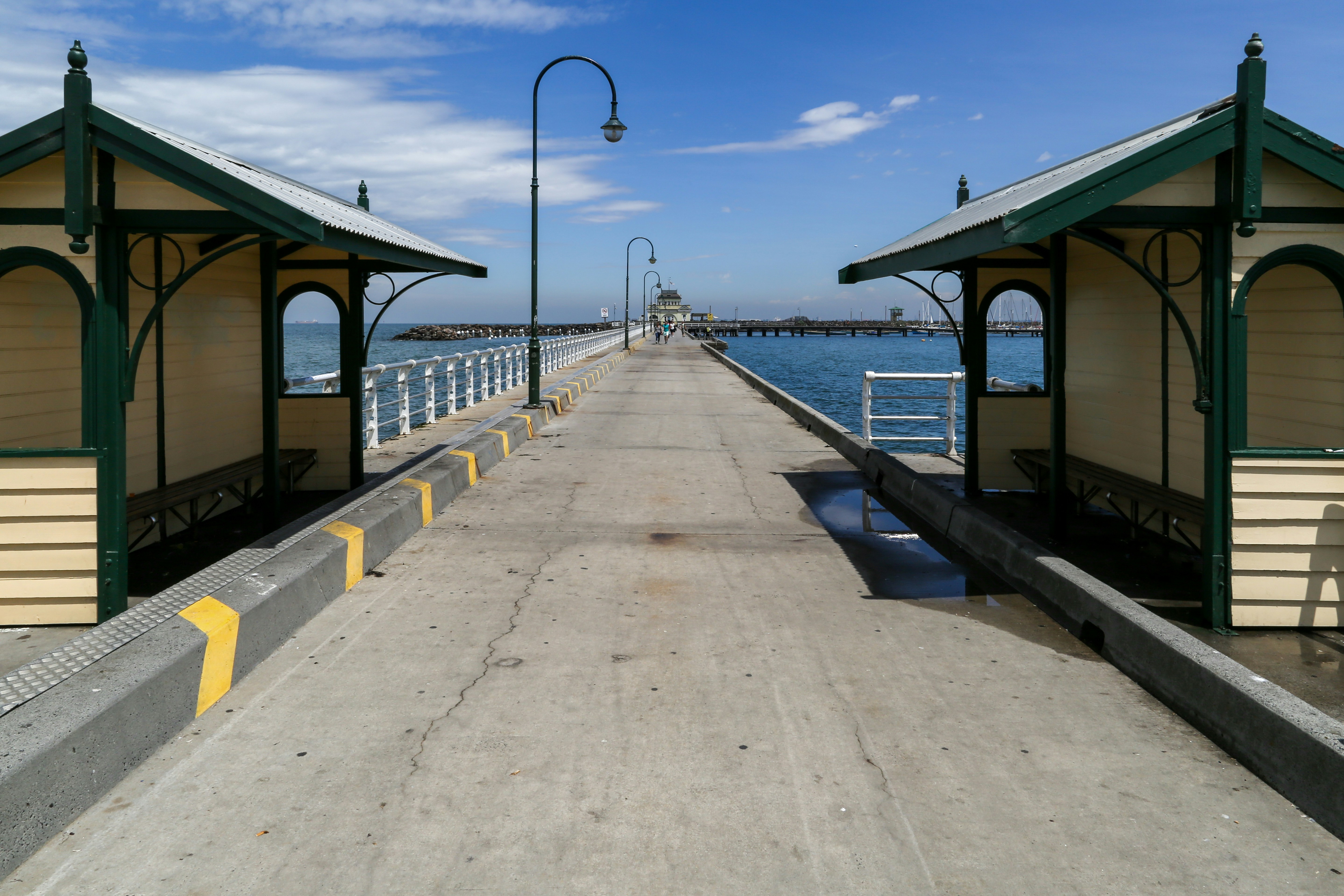Wooden pier flanked by charming shelters, leading towards the distant horizon and shimmering waters. The scene invites exploration and tranquility.