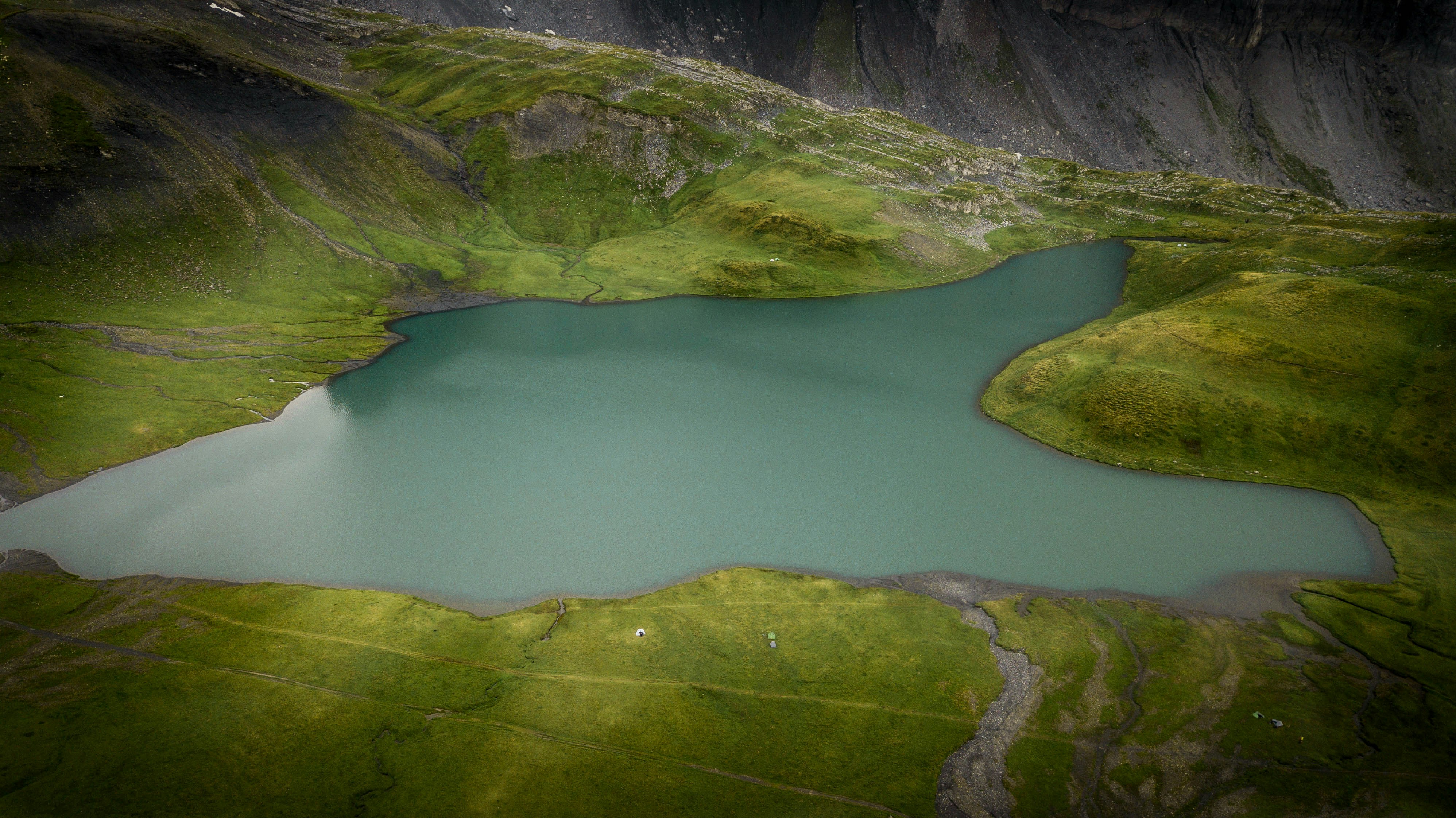 Turquoise lake nestled among verdant hills and rocky cliffs.