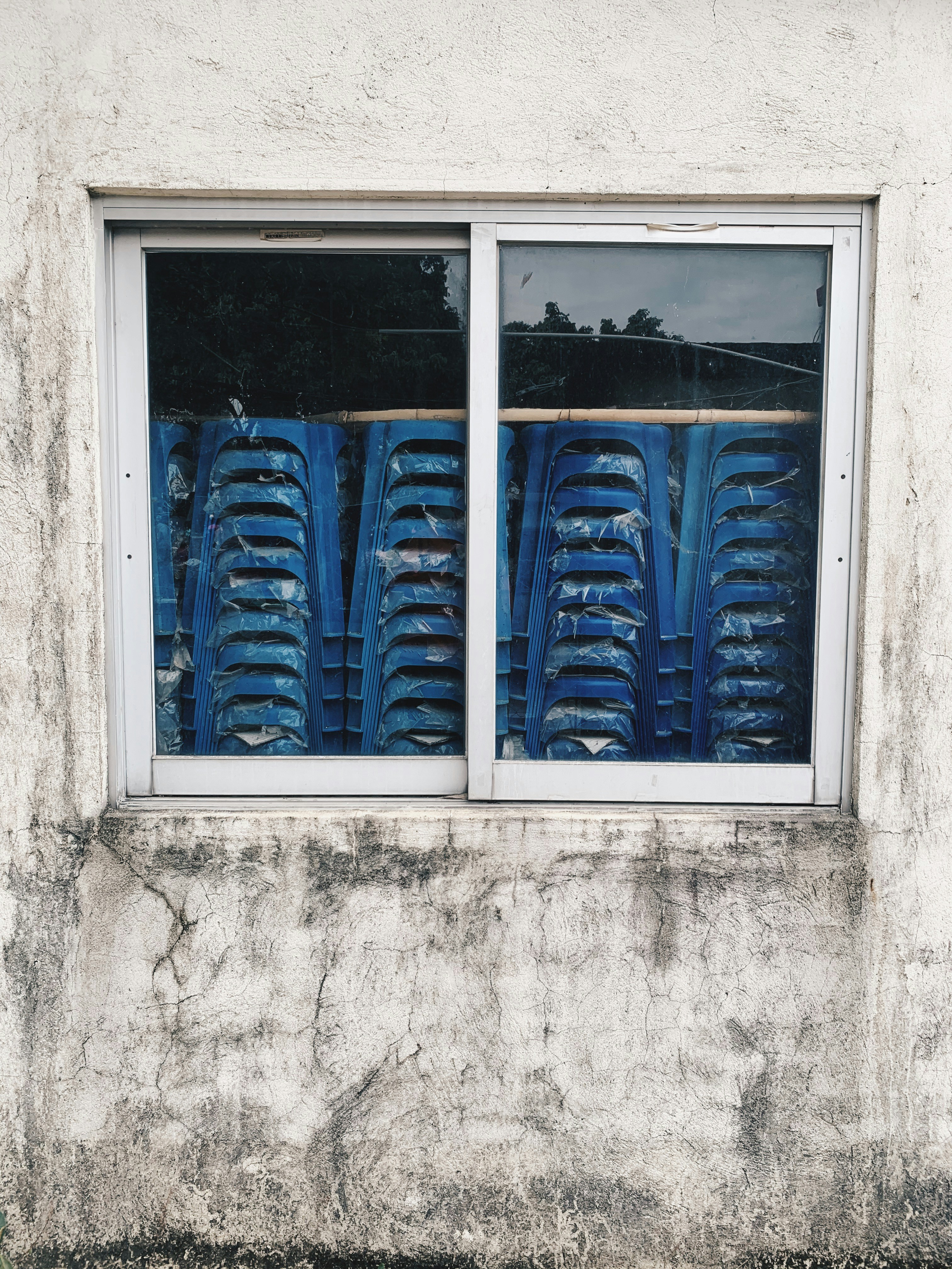 Stacks of Blue Chairs Framed by a Weathered Window